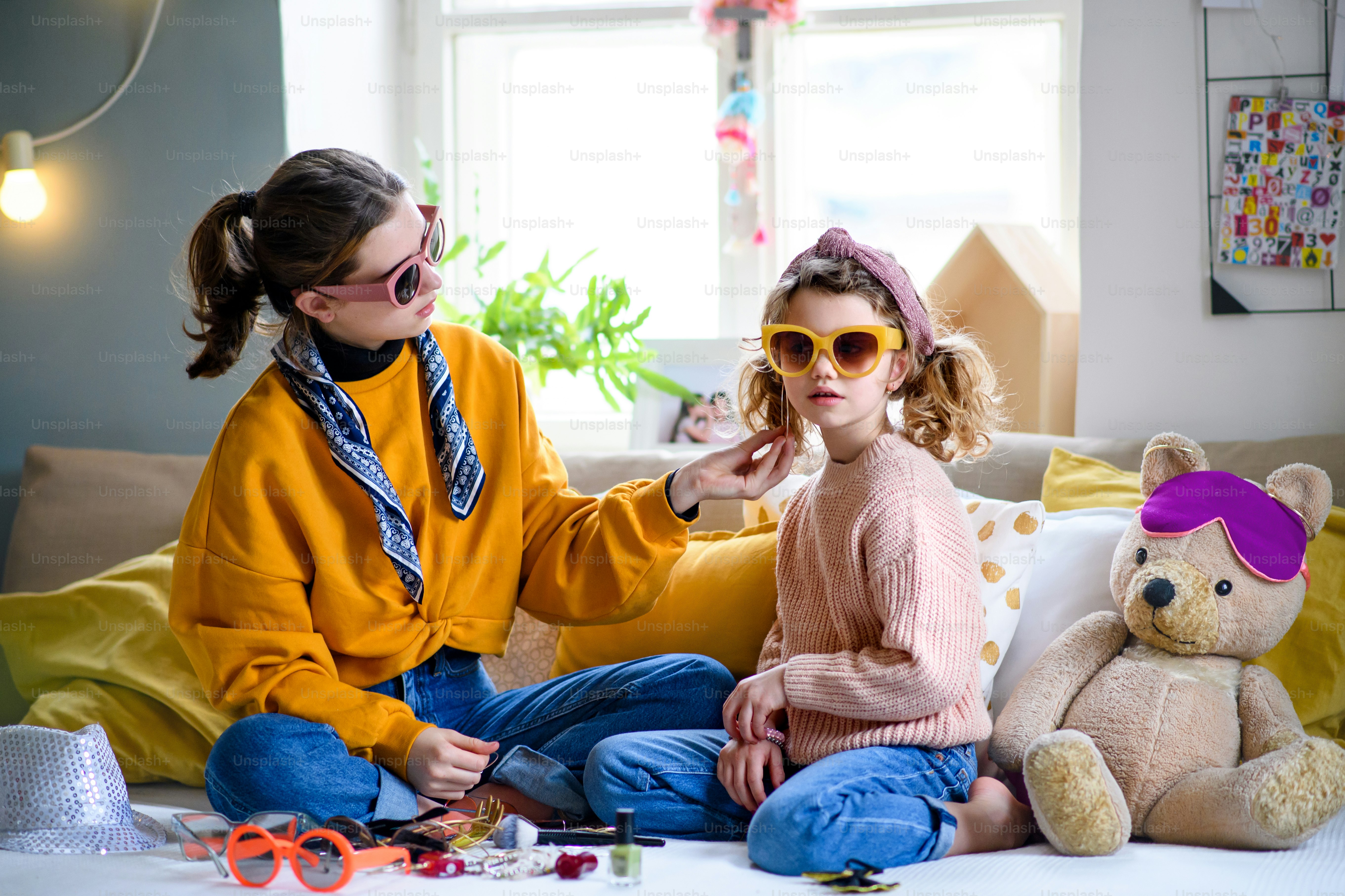 Portrait of sisters indoors at home, playing on bed. Lockdown concept ...
