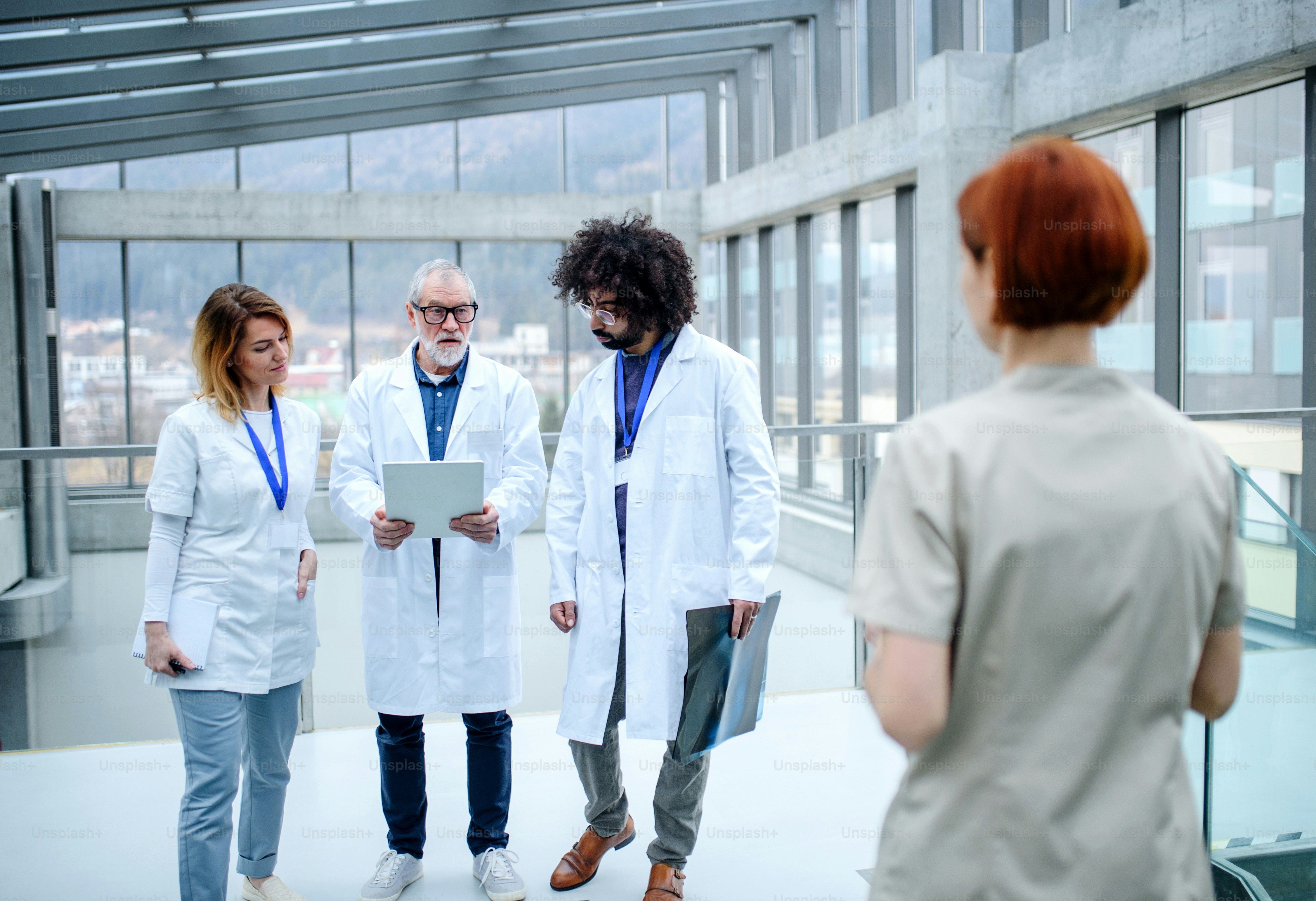 Group of doctors standing in corridor on medical conference, looking at ...