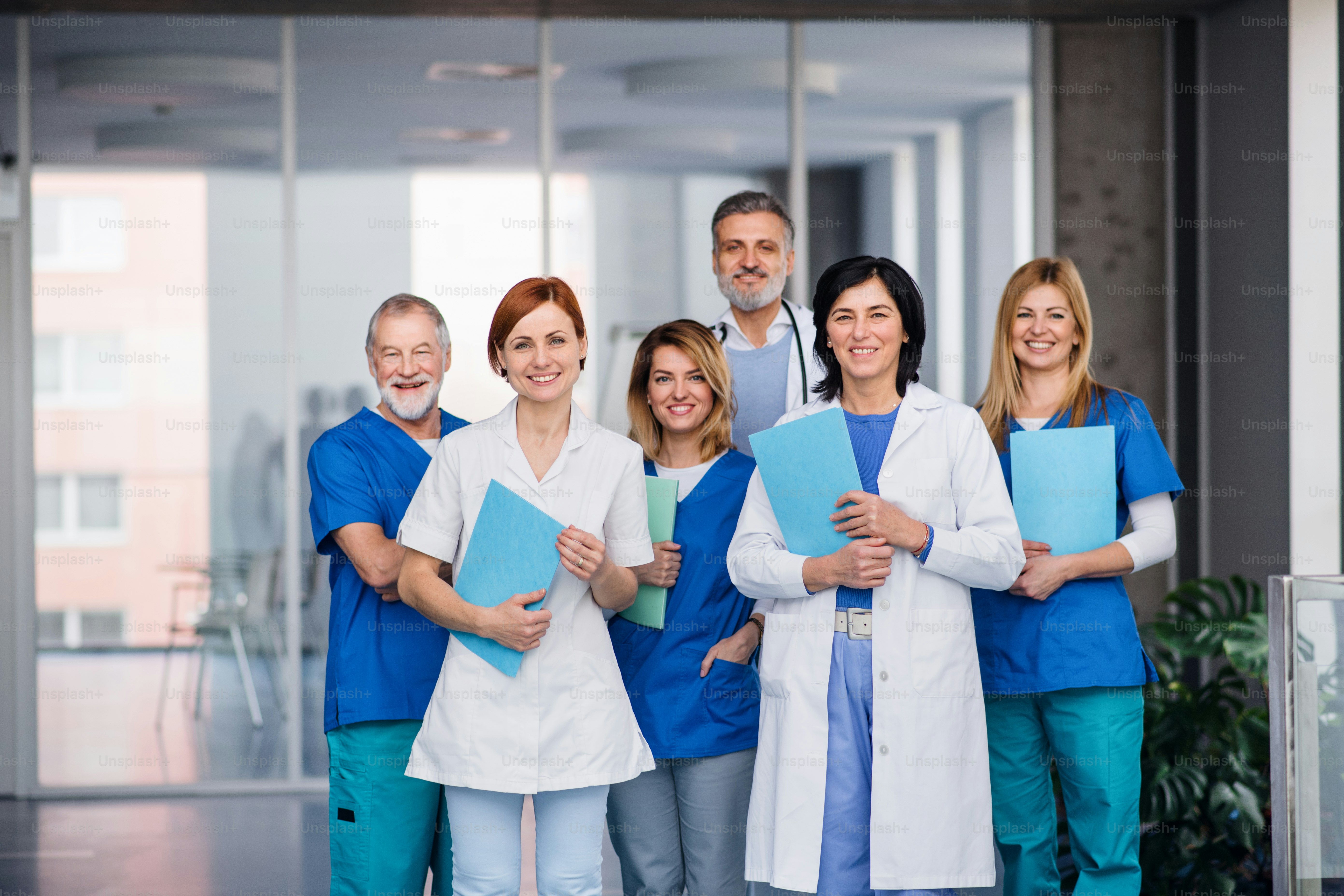 Group of doctors standing in corridor on medical conference, looking at ...