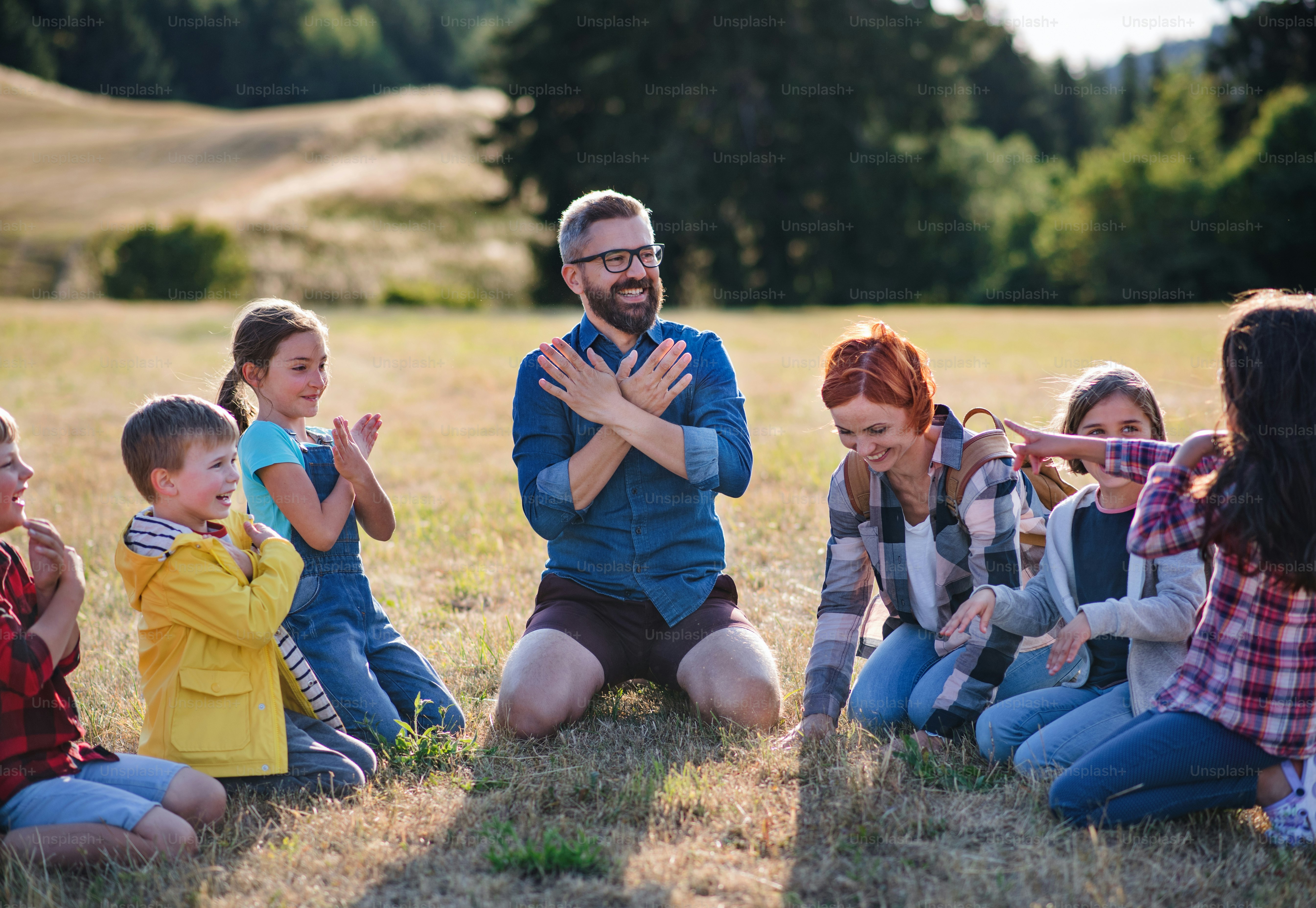 A group of small school children with teacher on field trip in nature ...