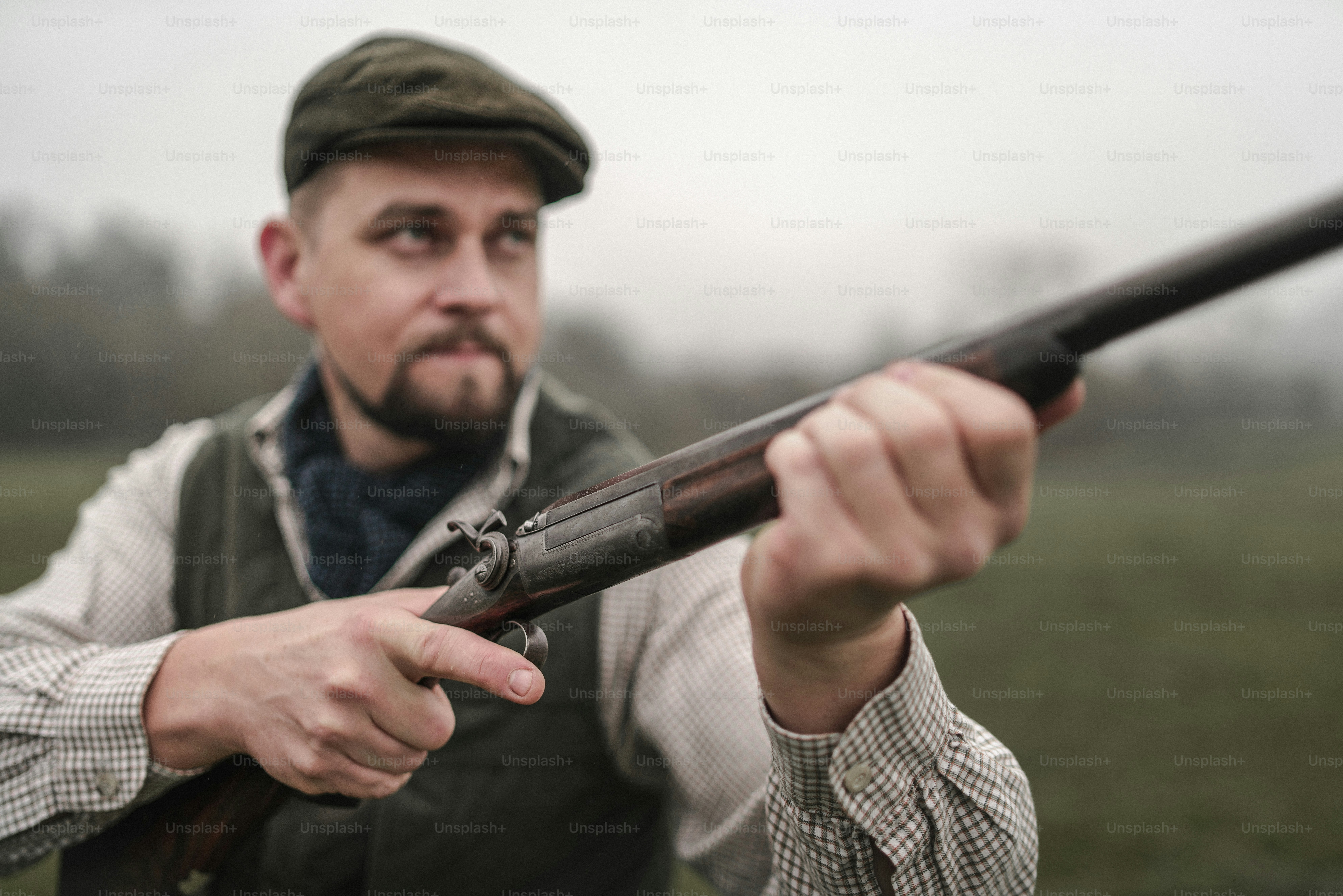 A hunter man in traditional shooting clothes on field aiming with ...
