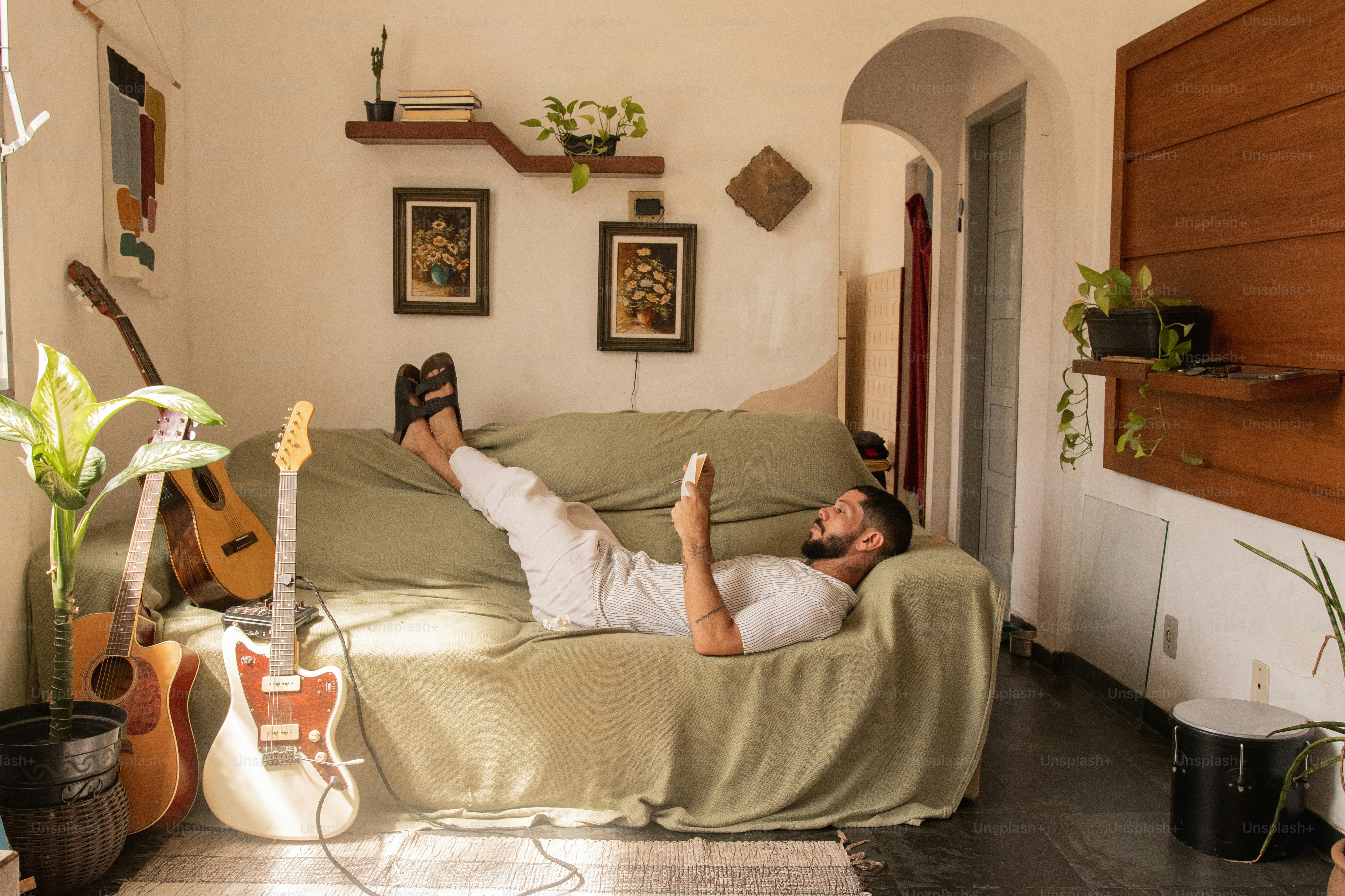 A man laying on a bed with a guitar photo – Couch potato Image on Unsplash
