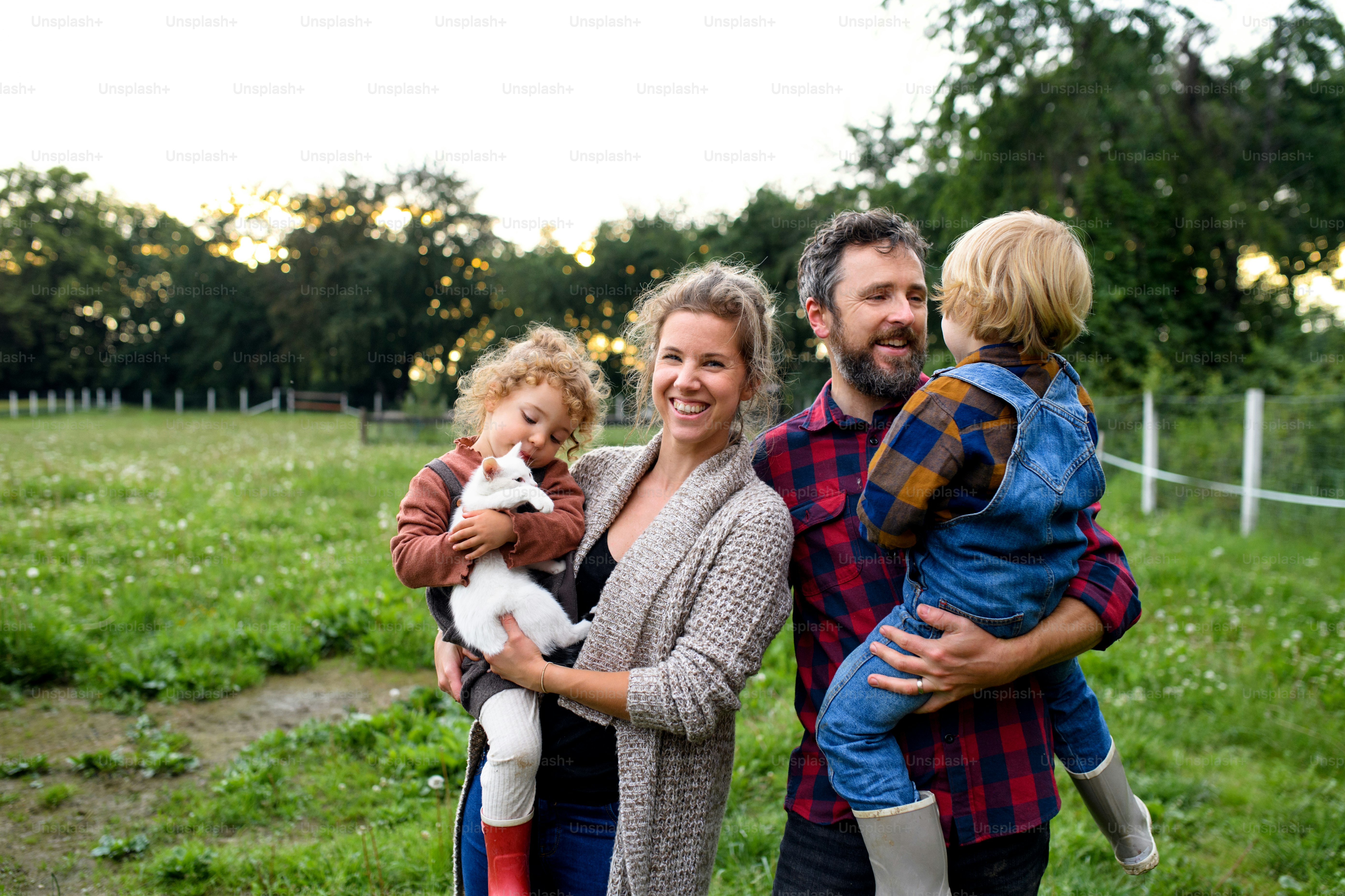 Portrait of happy family with small children standing on farm, resting ...