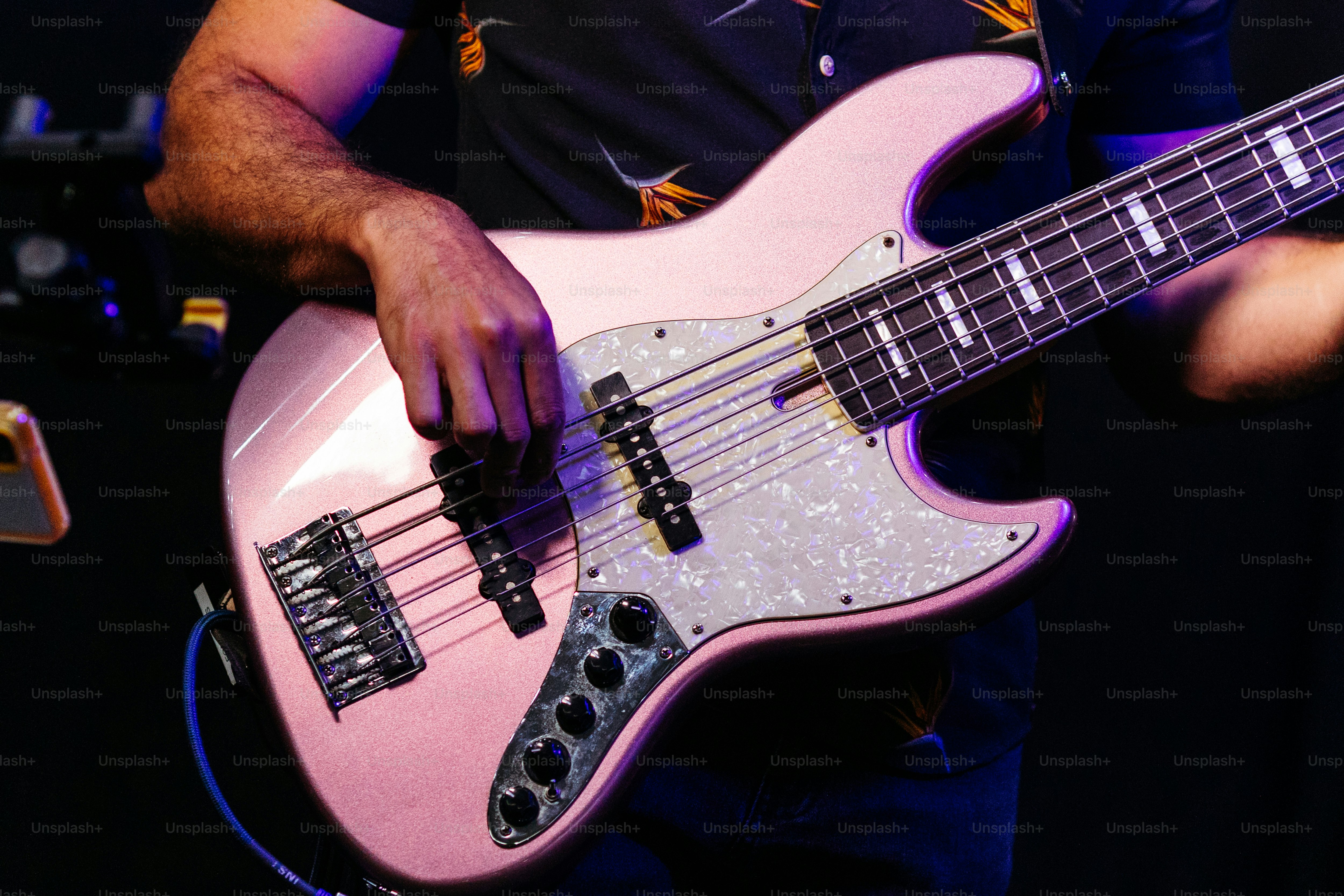 A man is playing a pink bass guitar photo – Bass guitar Image on Unsplash
