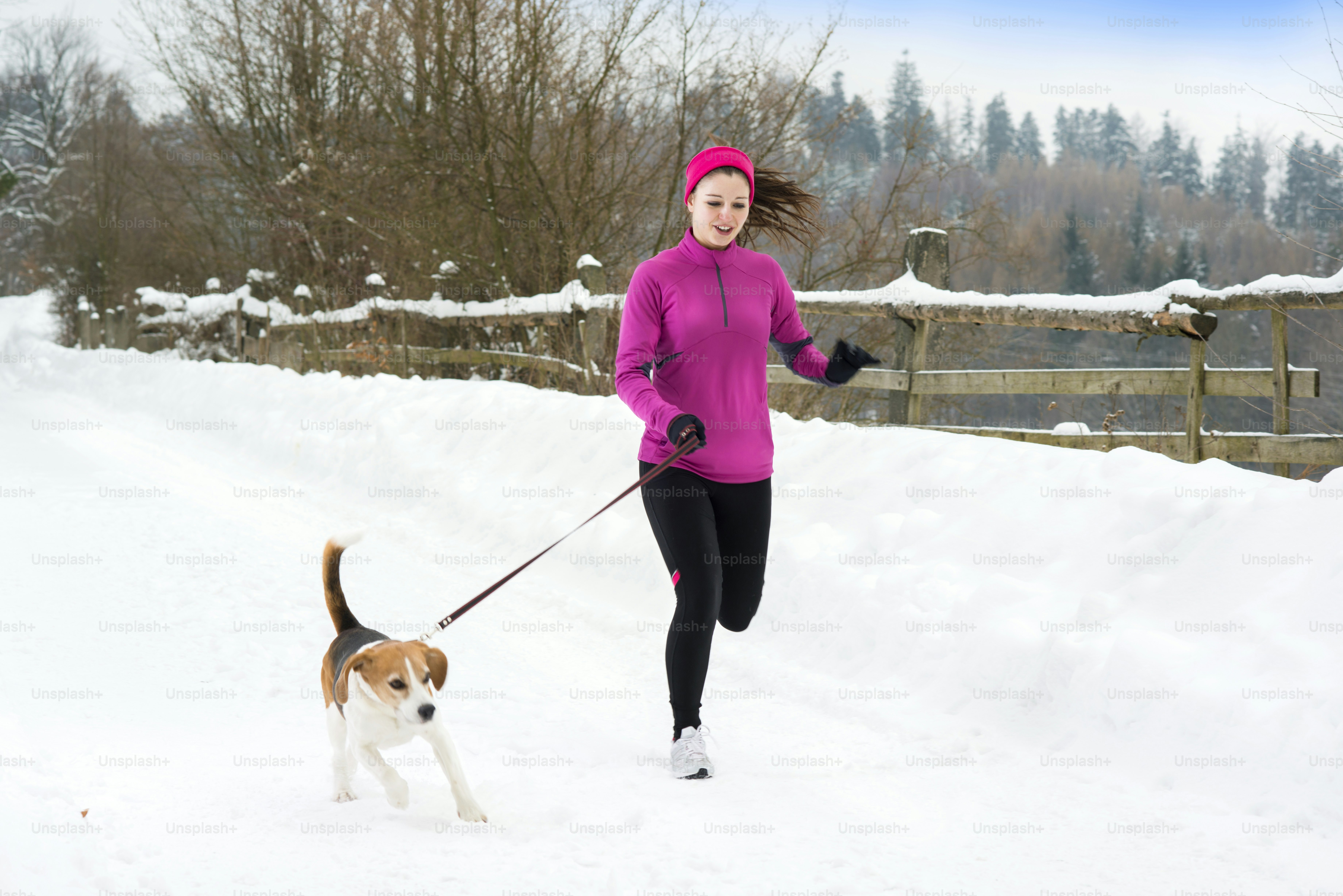 Athlete woman is running during winter training outside in cold snow ...