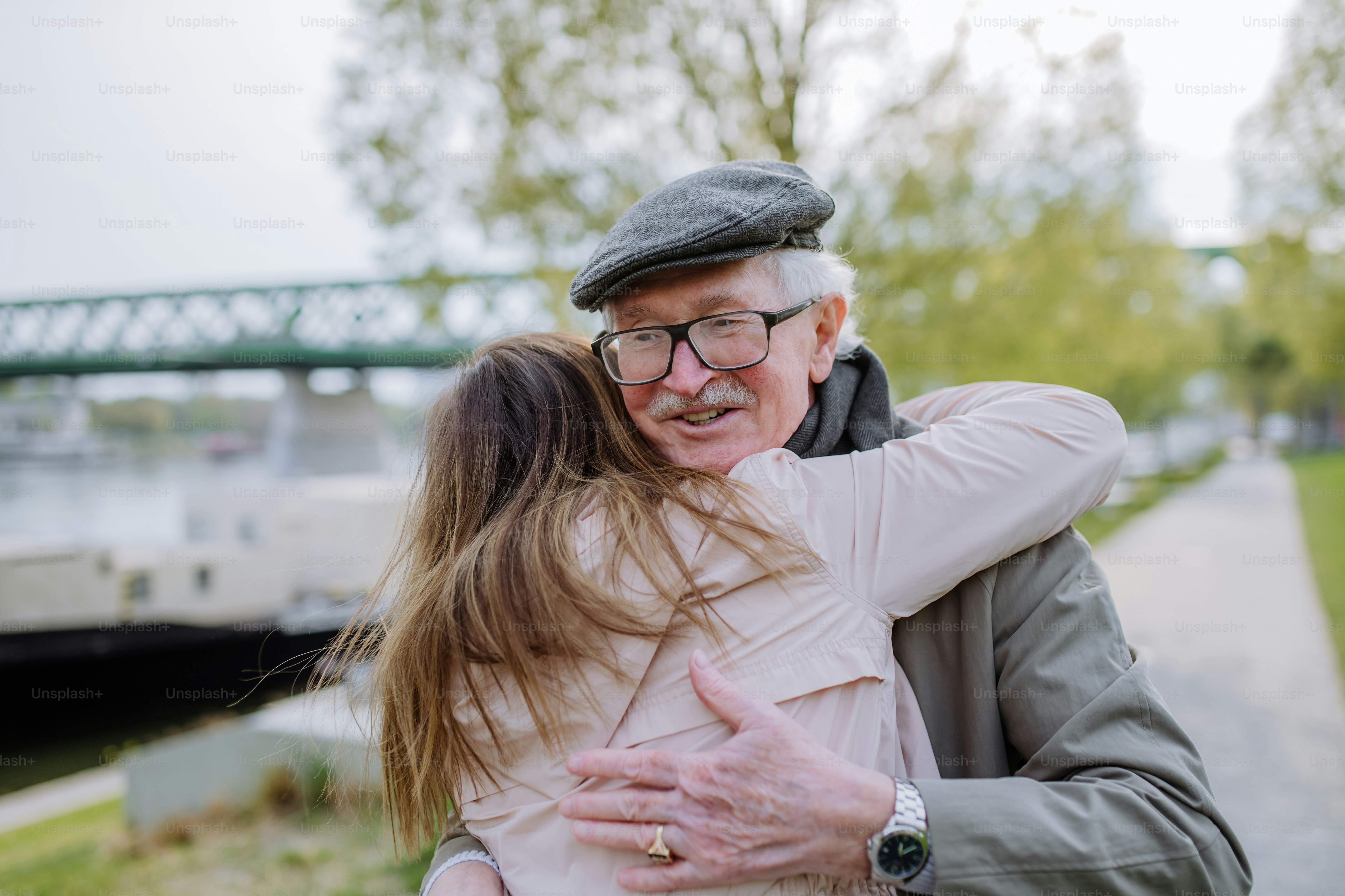 A rear view of adult daughter hugging her senior father when meeting ...