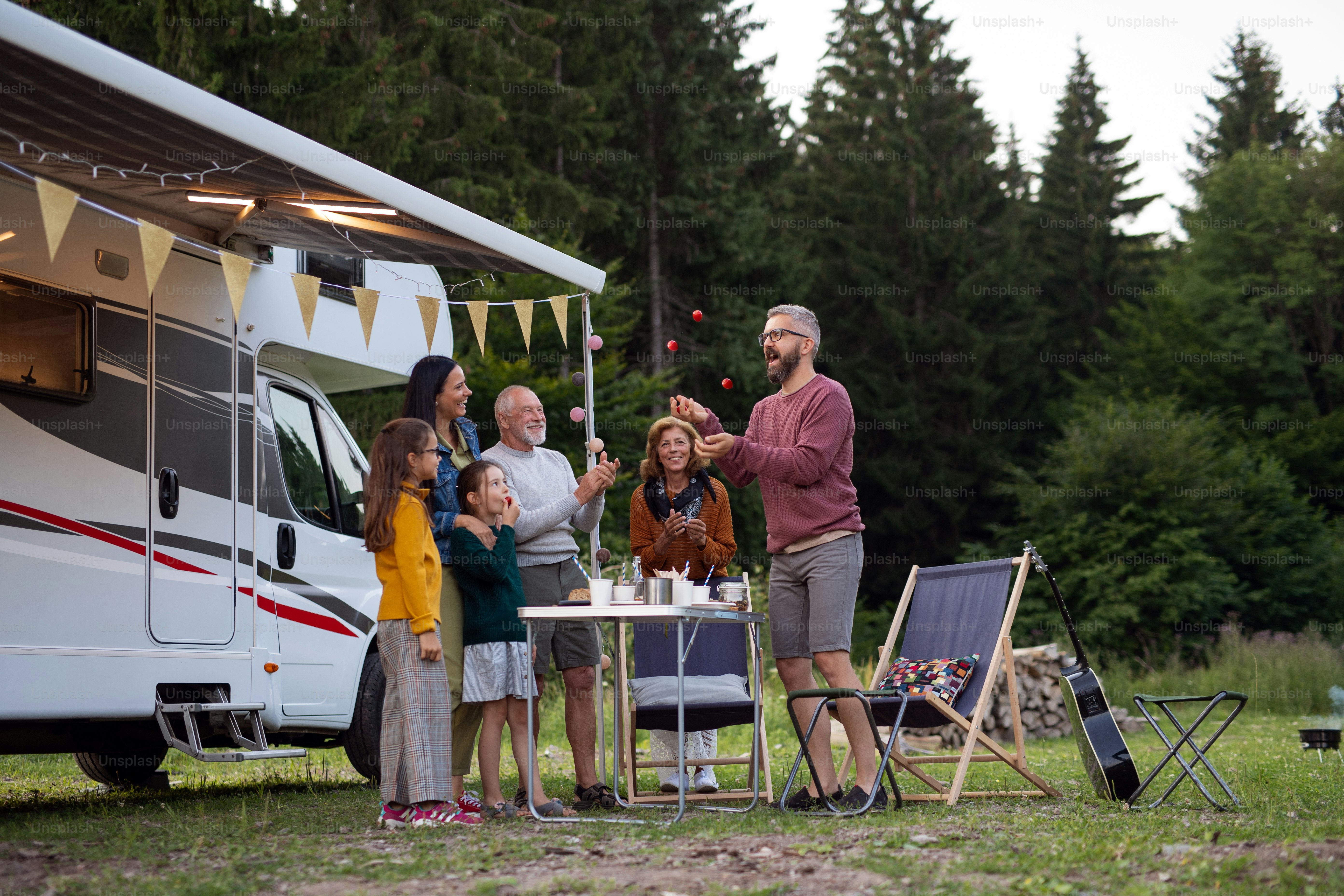 A multi-generation family standing and having fun outdoors by car ...