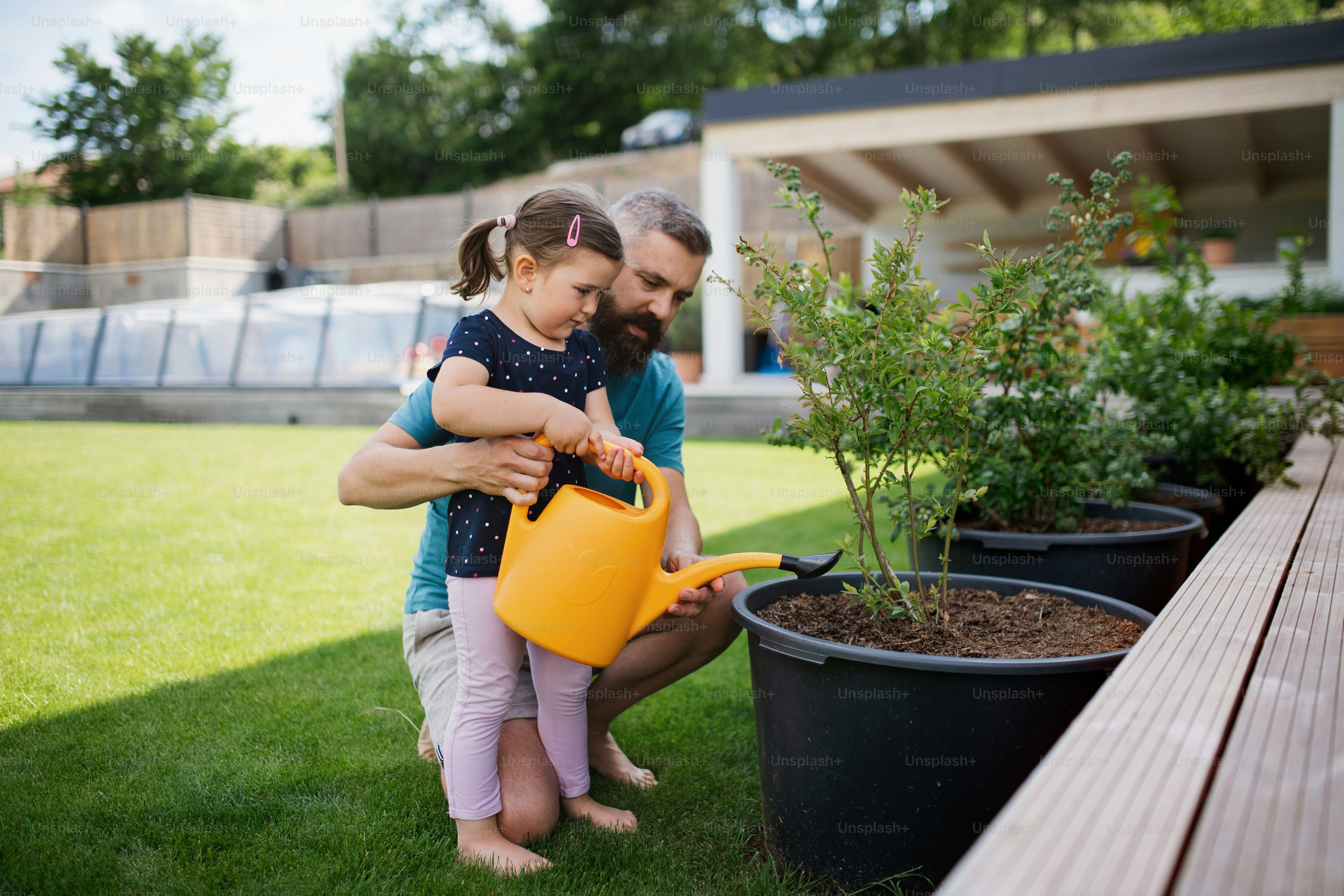 A father with three daughters playing outdoors in the backyard, running ...