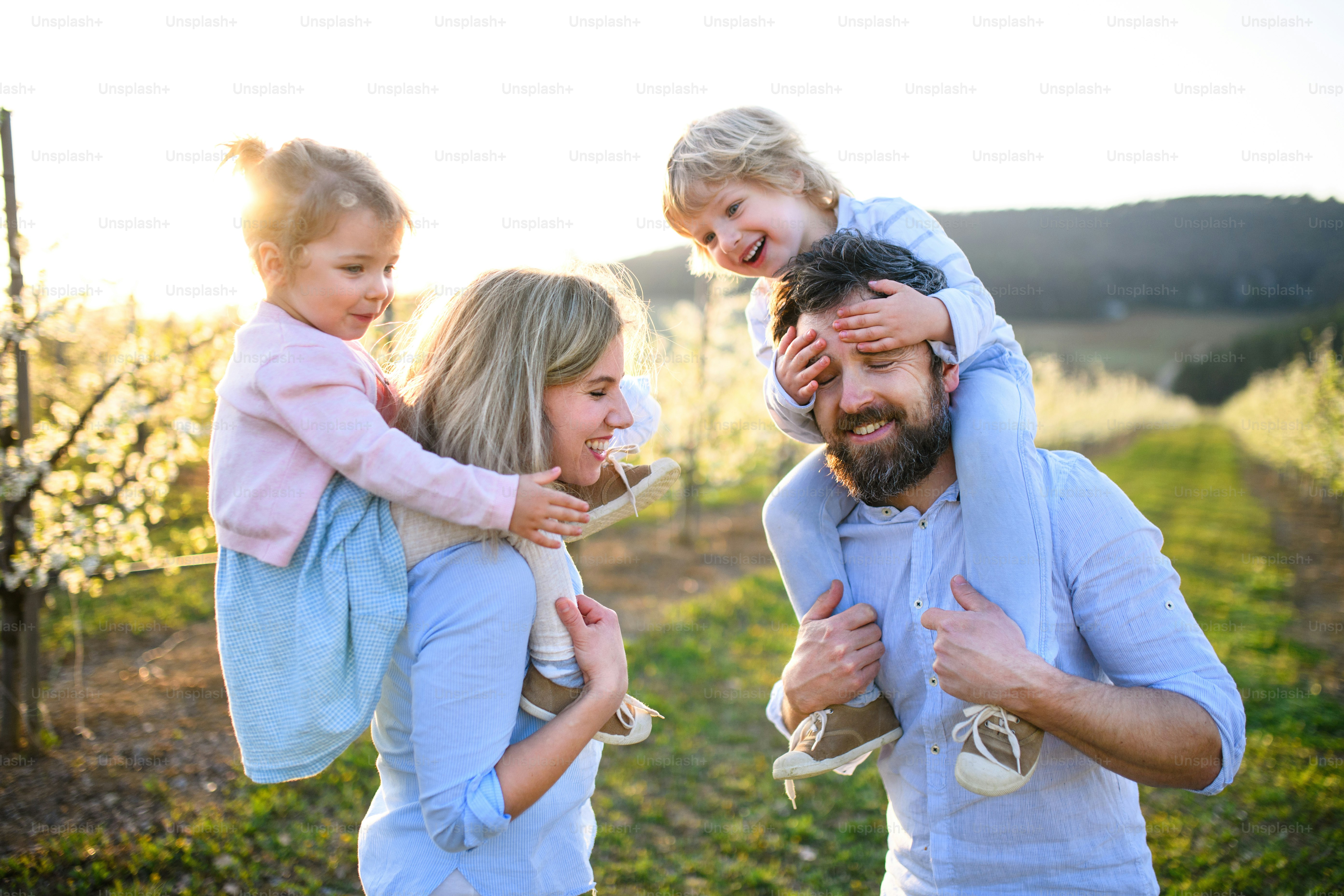 Front view of family with two small children standing outdoors in ...