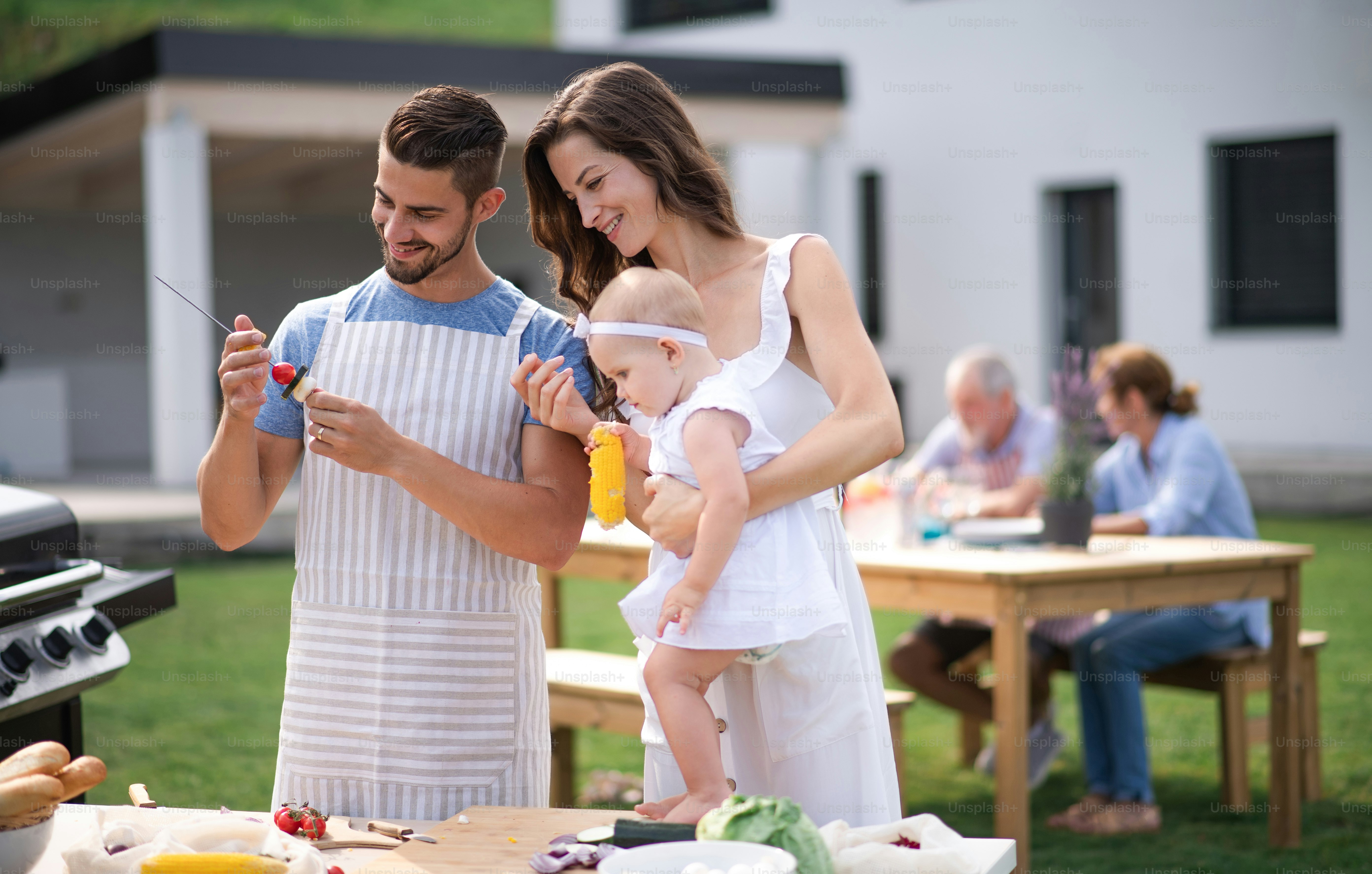 Portrait of happy family with baby outdoors on garden barbecue ...