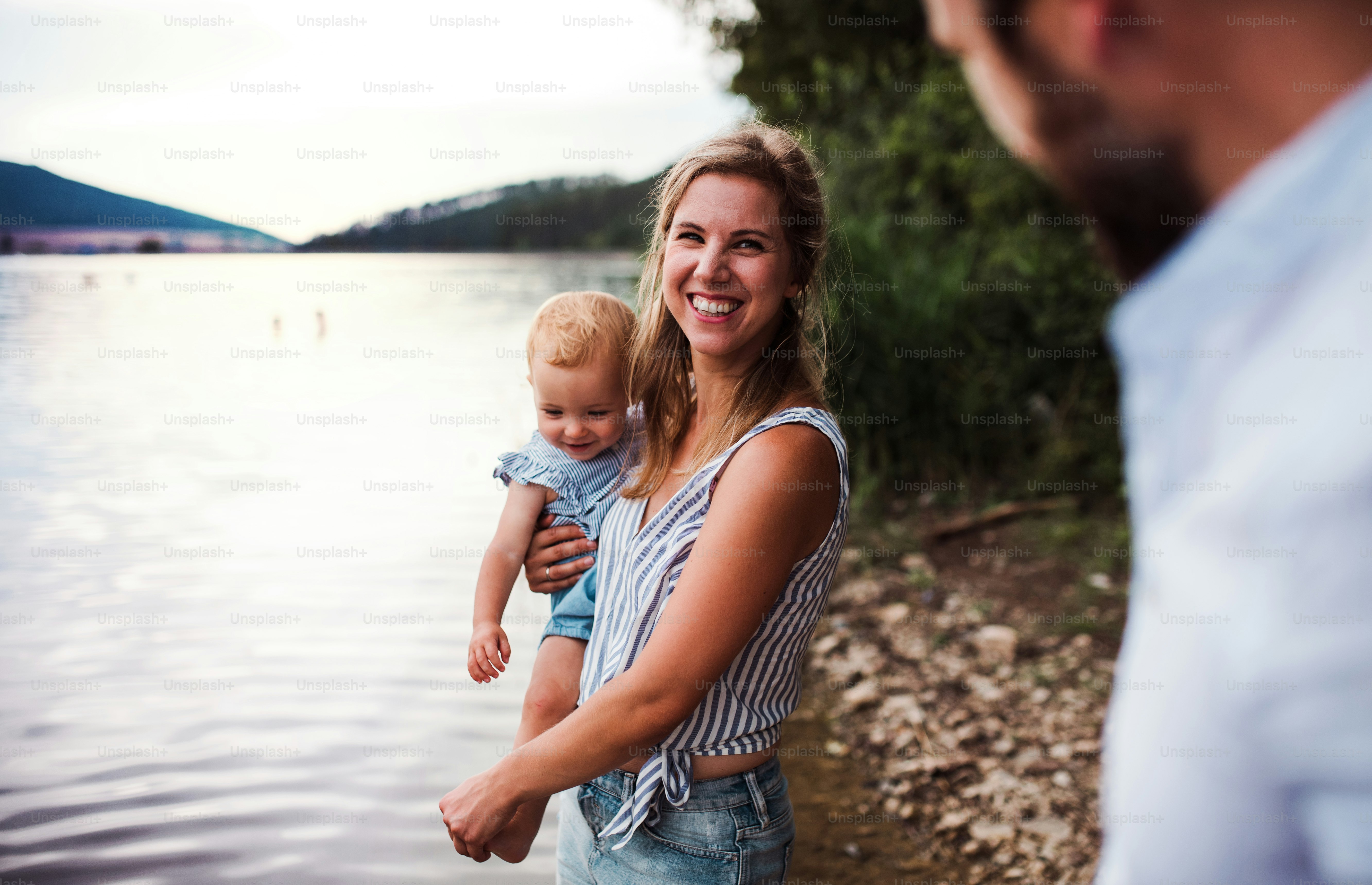 A mother with a toddler daughter outdoors by the river in summer, laughing. photo – Summer Image ...