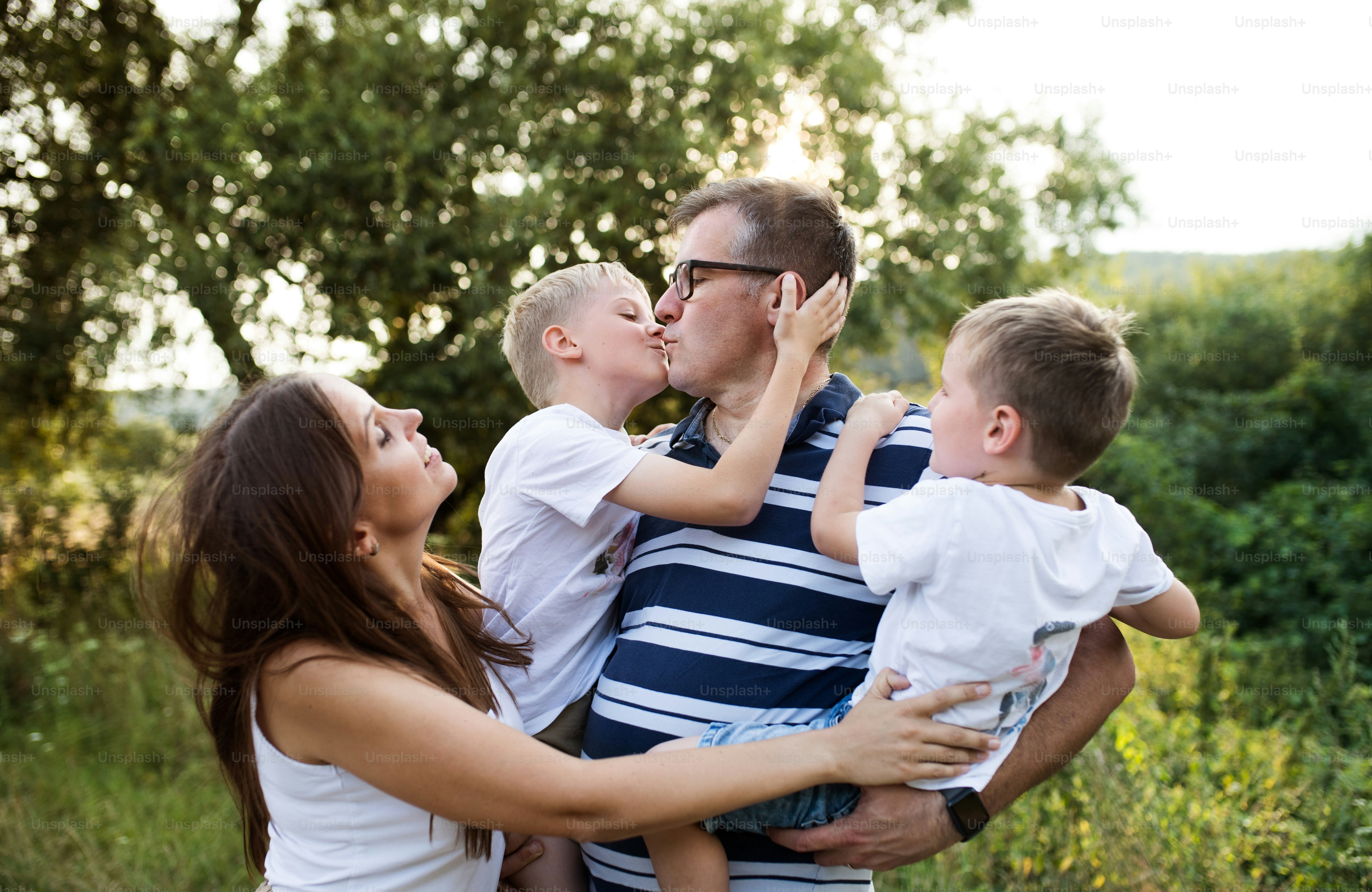 Une jeune famille joyeuse tenant deux jeunes fils à l’extérieur dans la ...