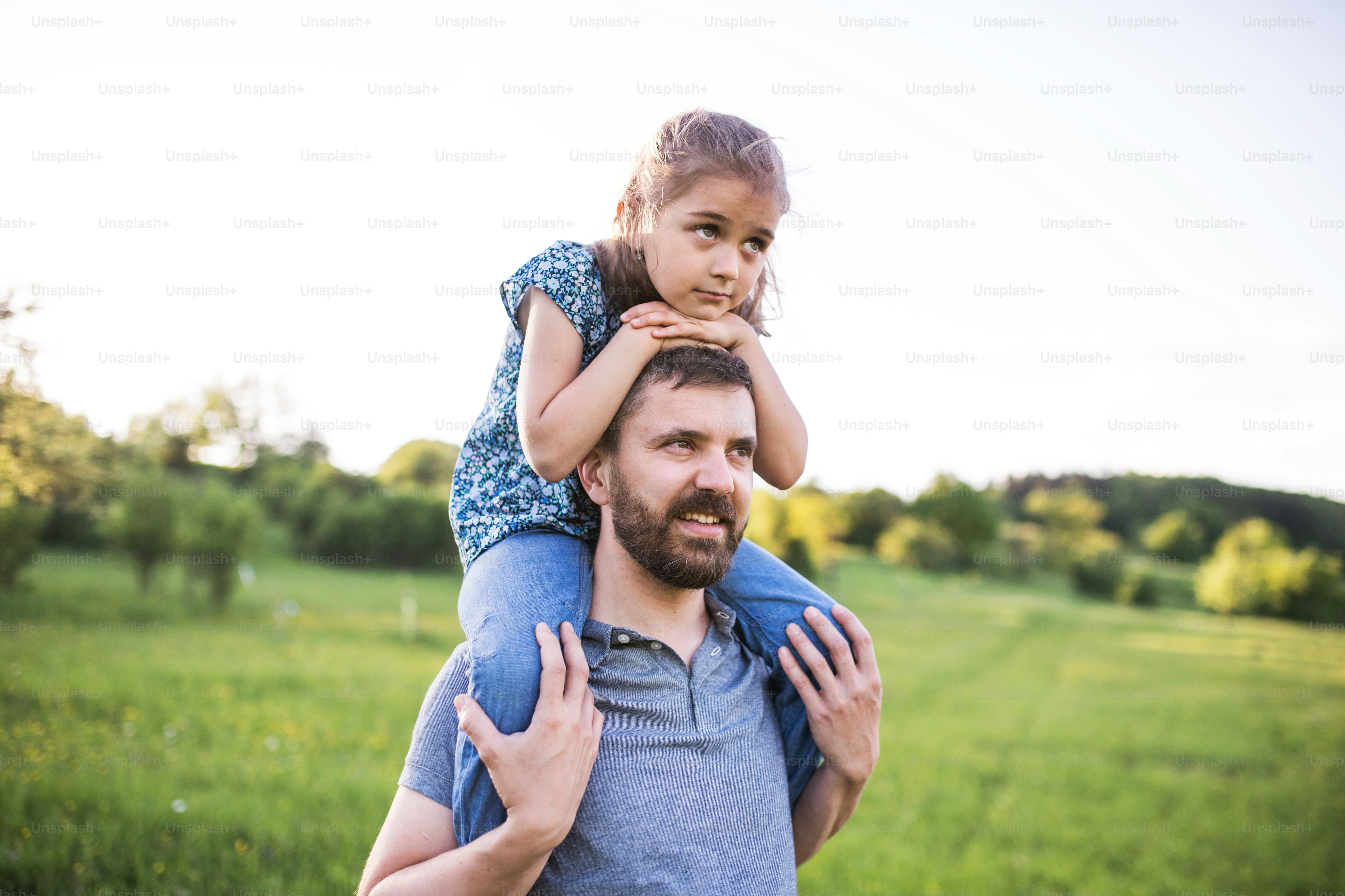Mature father giving a small daughter a piggyback ride in spring nature ...