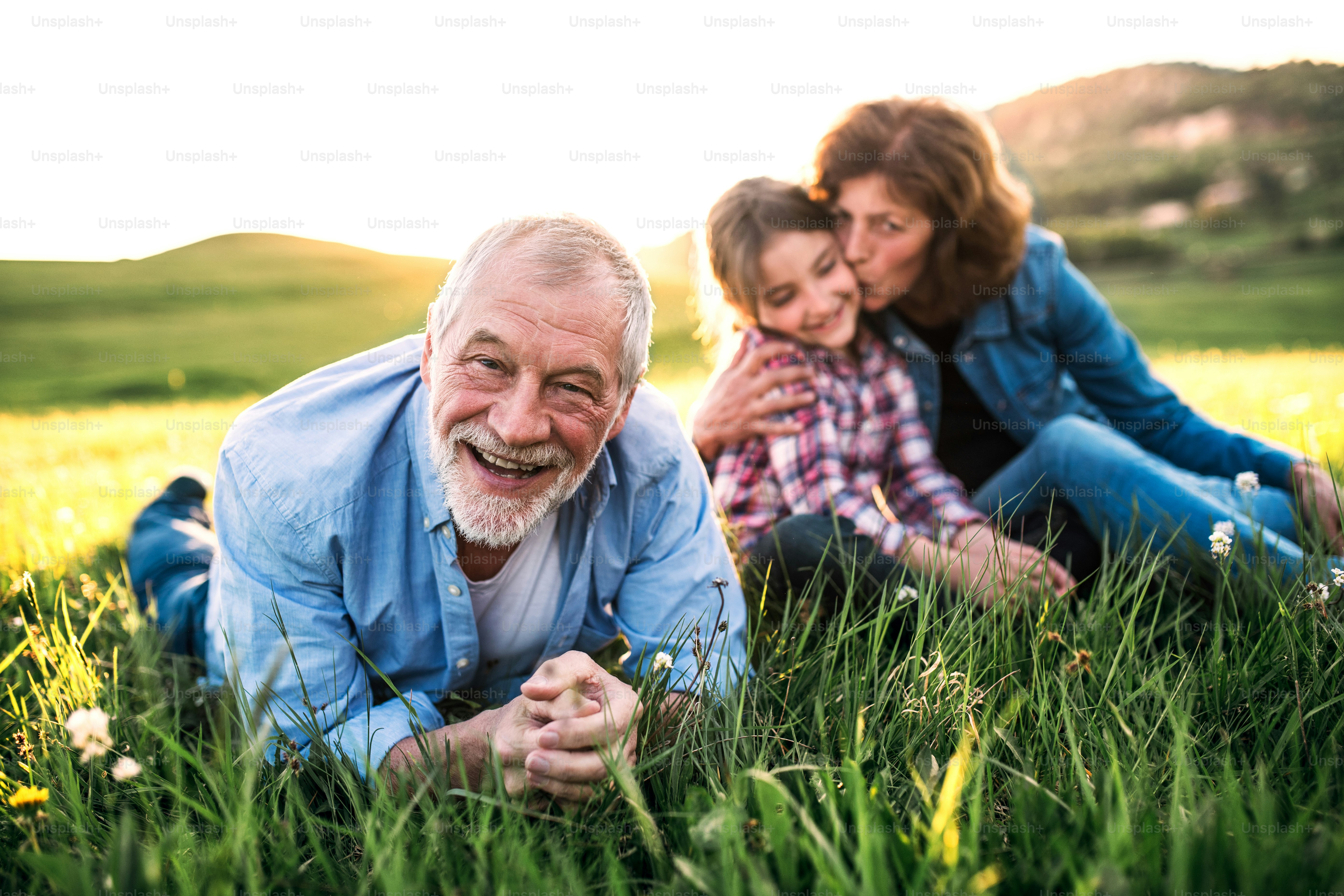 Senior couple with granddaughter walking and jumping outside in spring ...