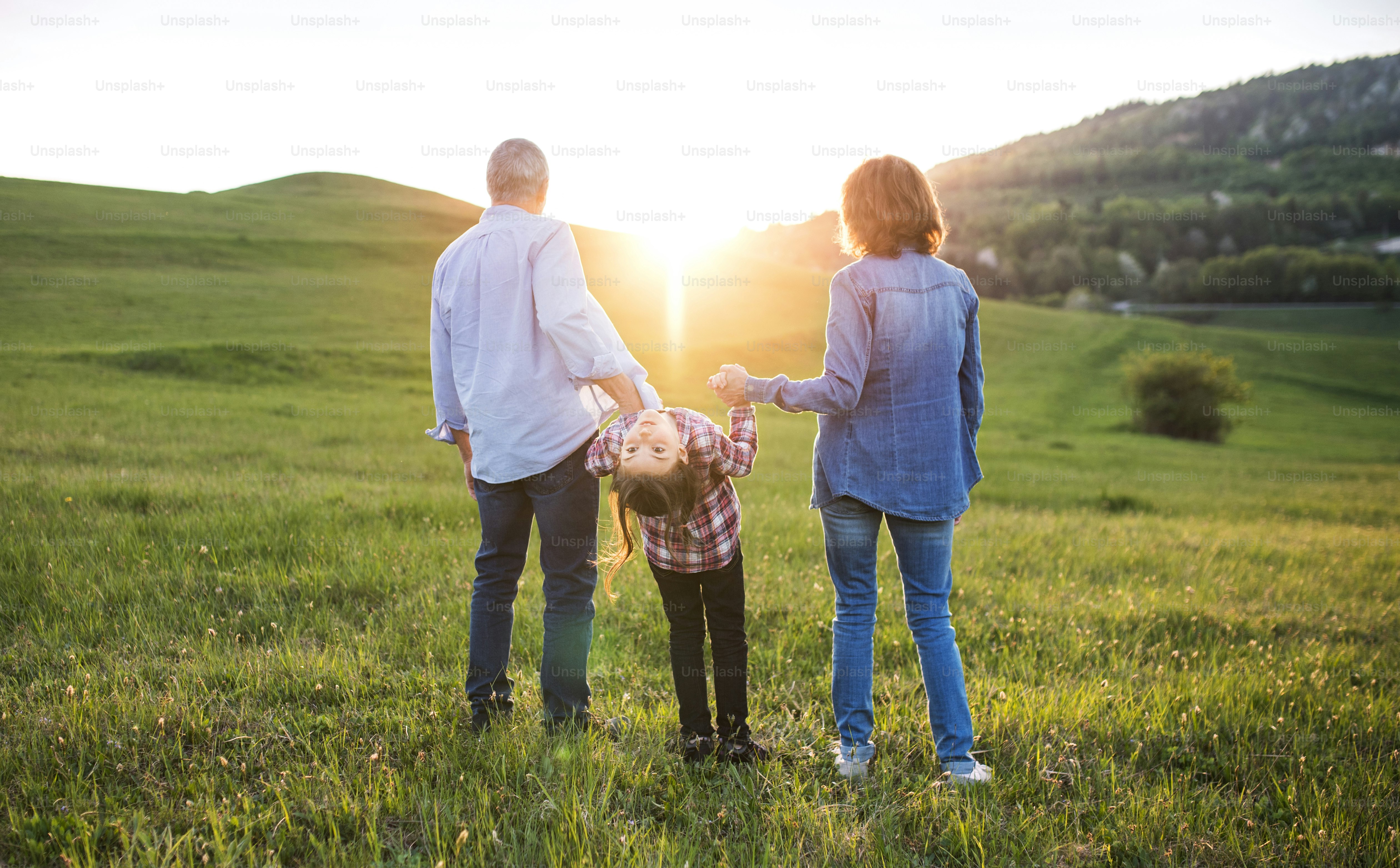 A happy small girl with her unrecognizable senior grandparents having ...