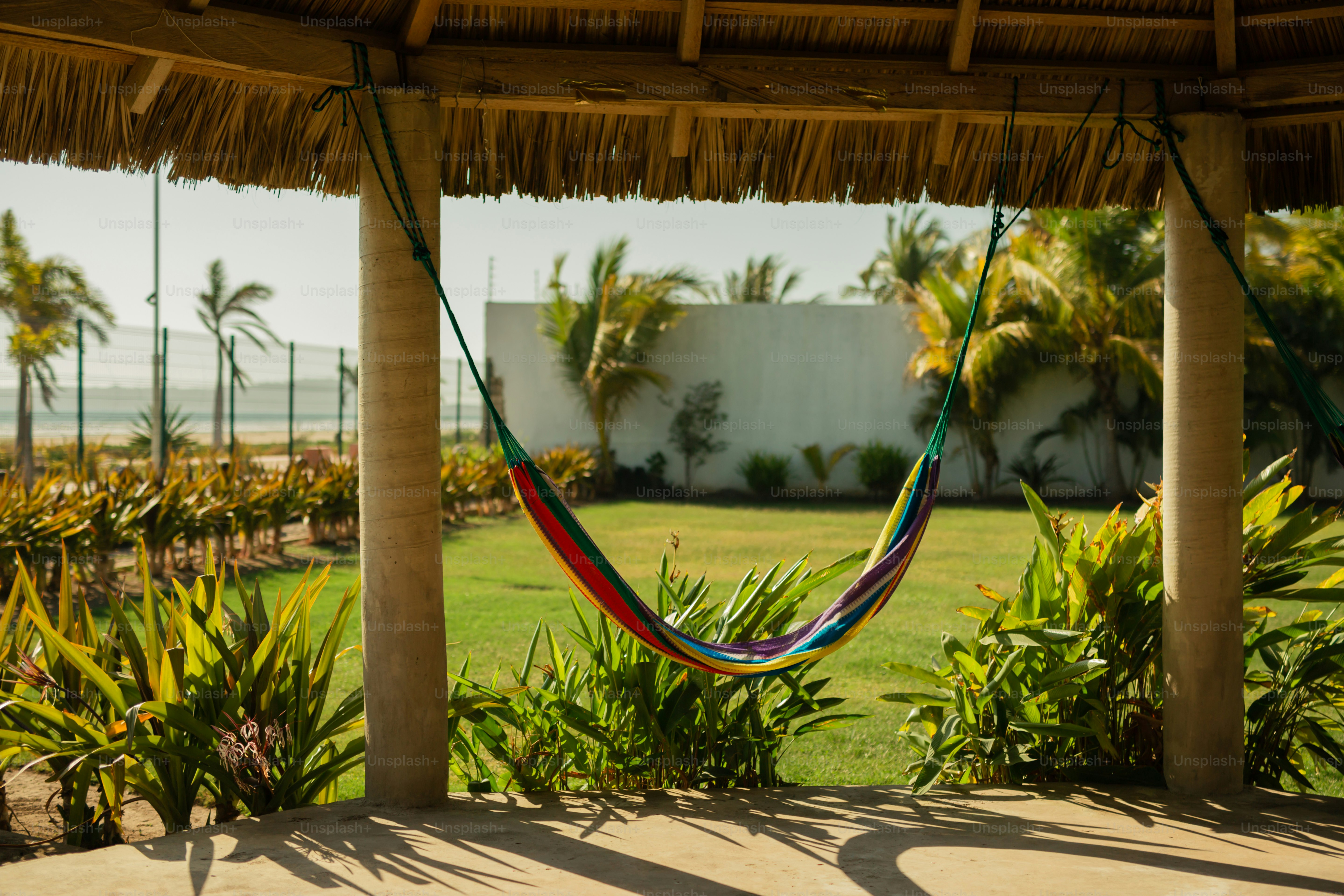 A hammock hanging from a thatched roof photo – Luxury Image on Unsplash