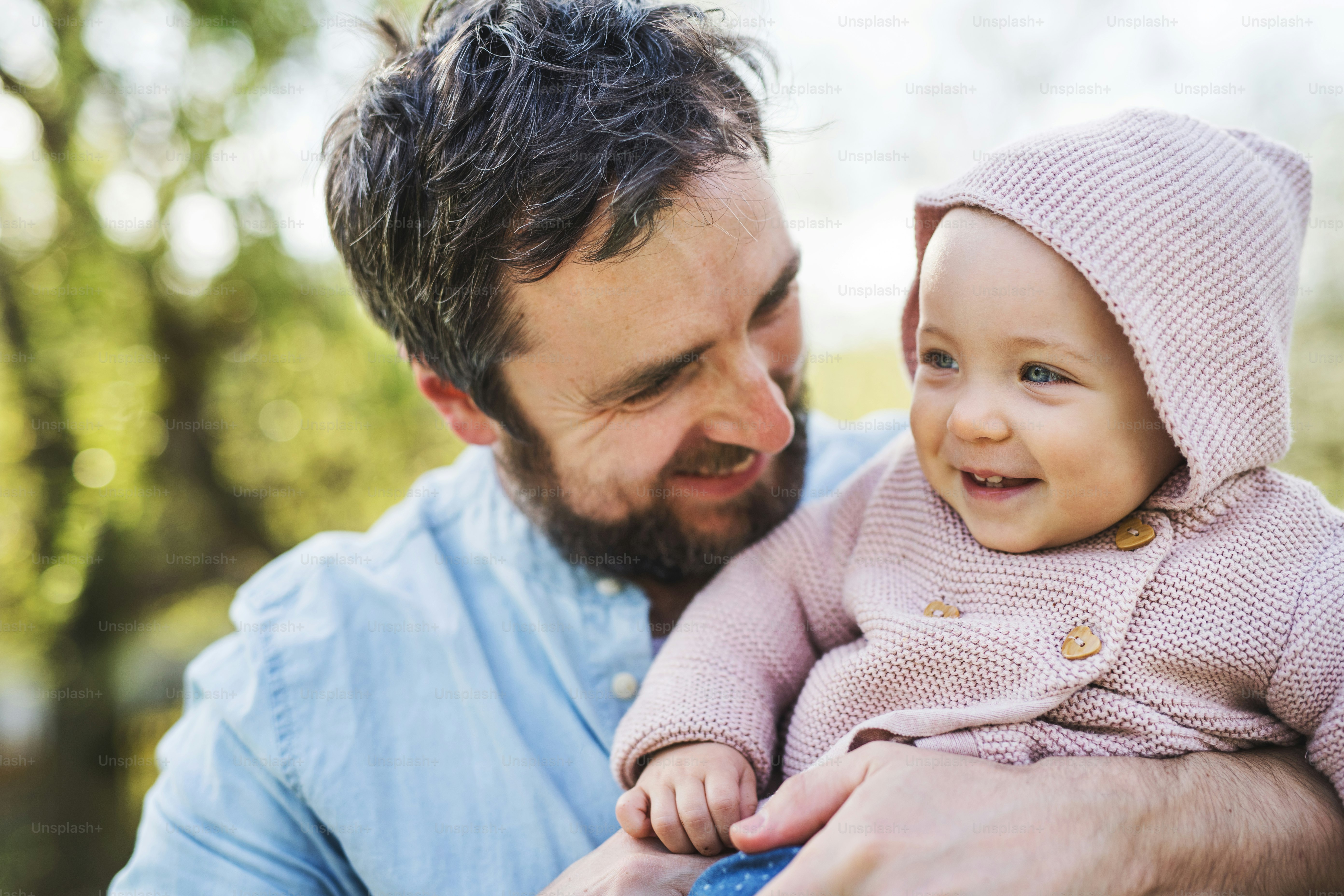 A father with his toddler daughter outside in green sunny spring nature ...