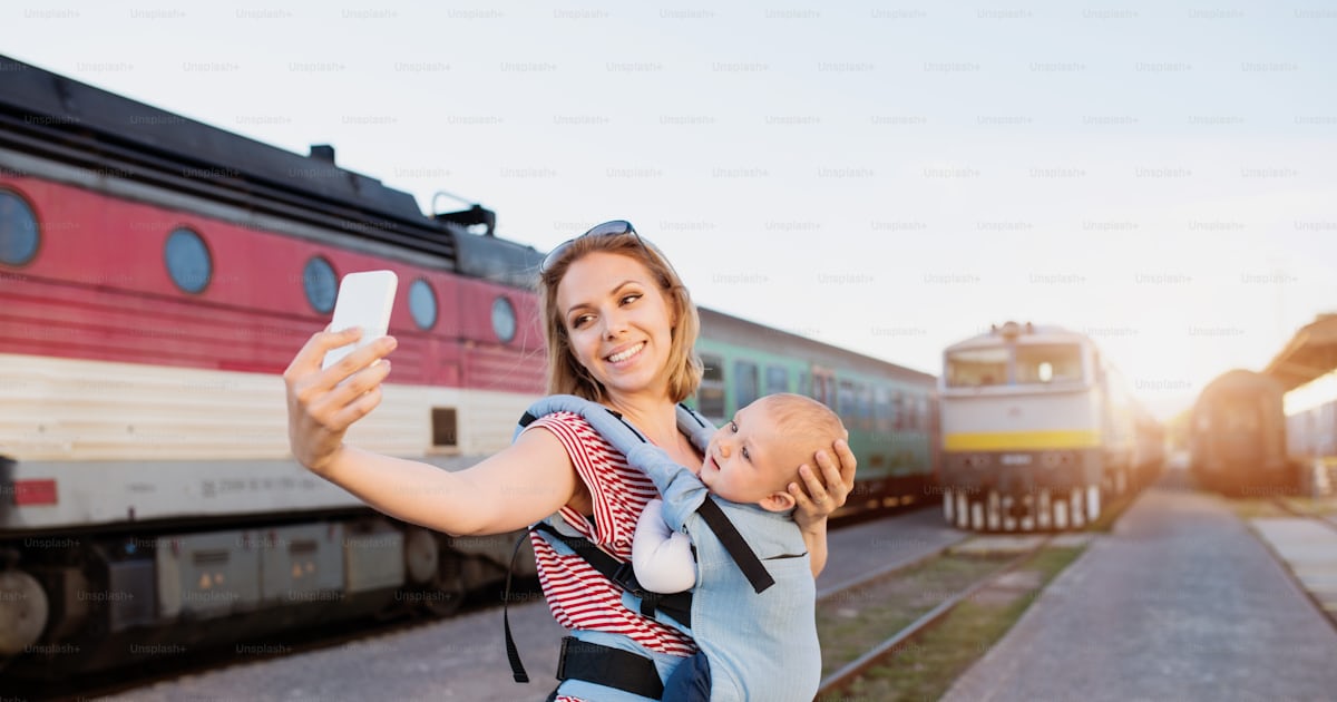 男の子と一緒に電車で旅行する若い母親。駅でスマートフォンを持つ女性と息子。の写真 Unsplashの旅行の画像