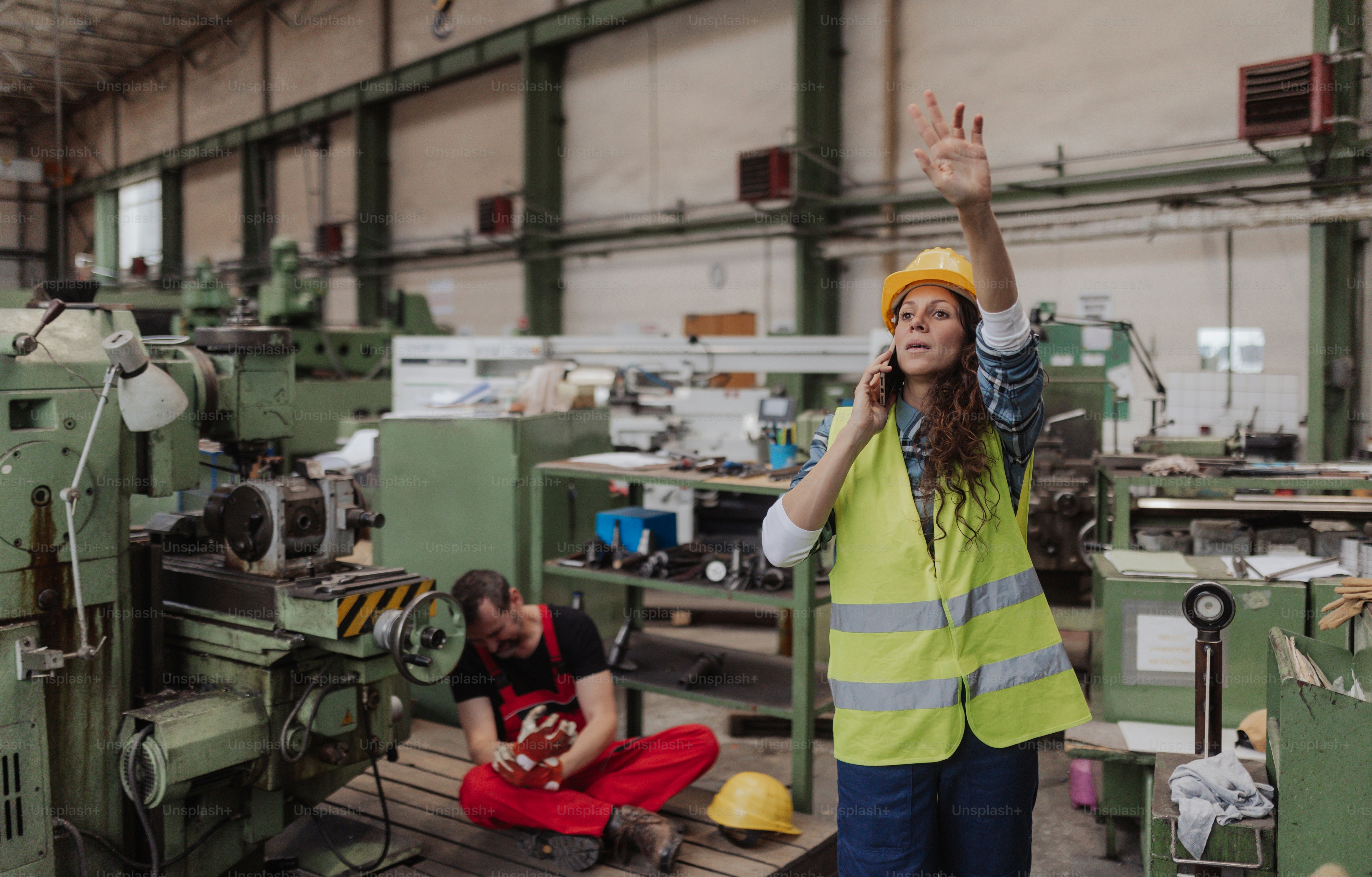 A woman is helping her colleague after accident in factory. First aid ...