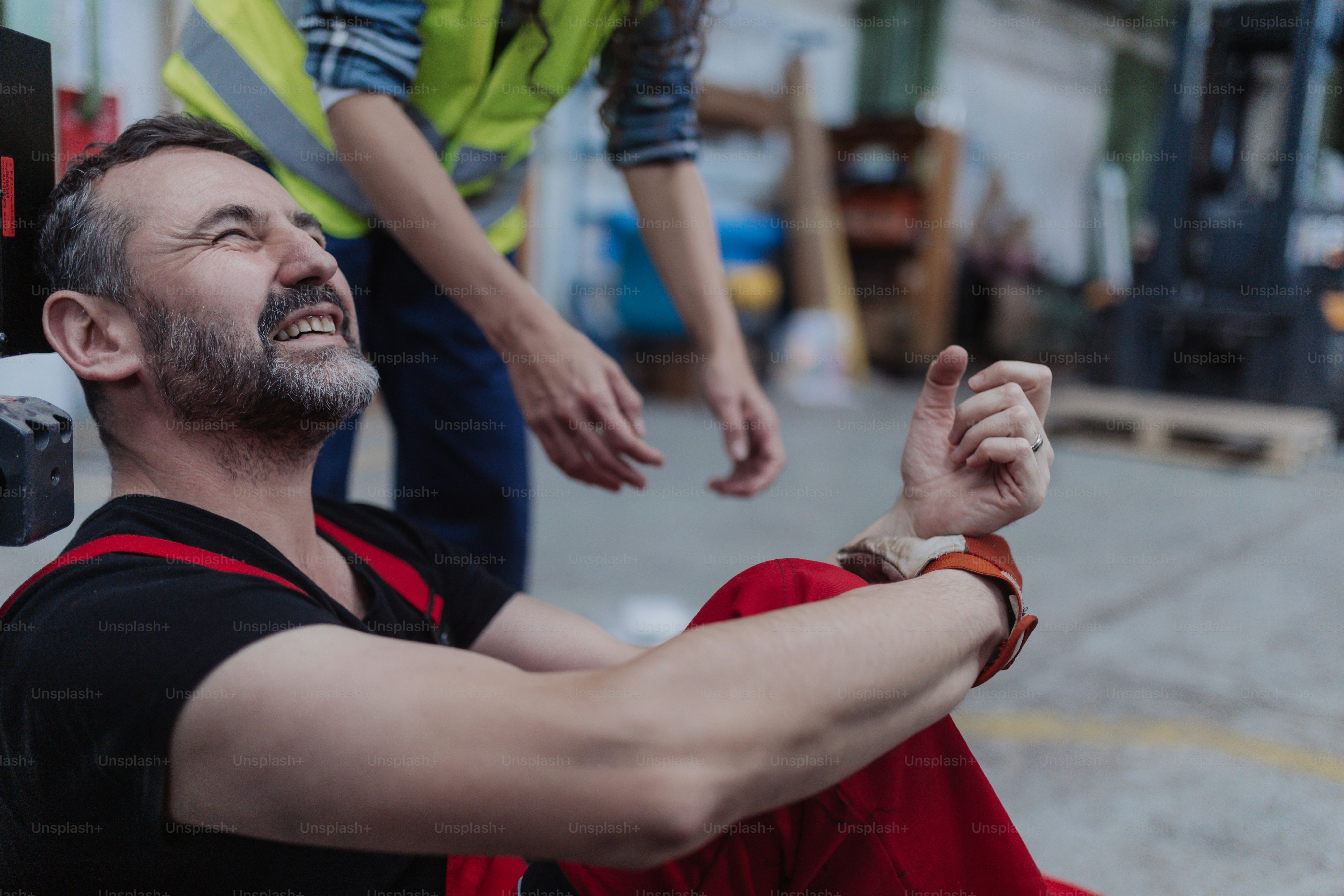A woman is helping her colleague after accident in factory. First aid ...
