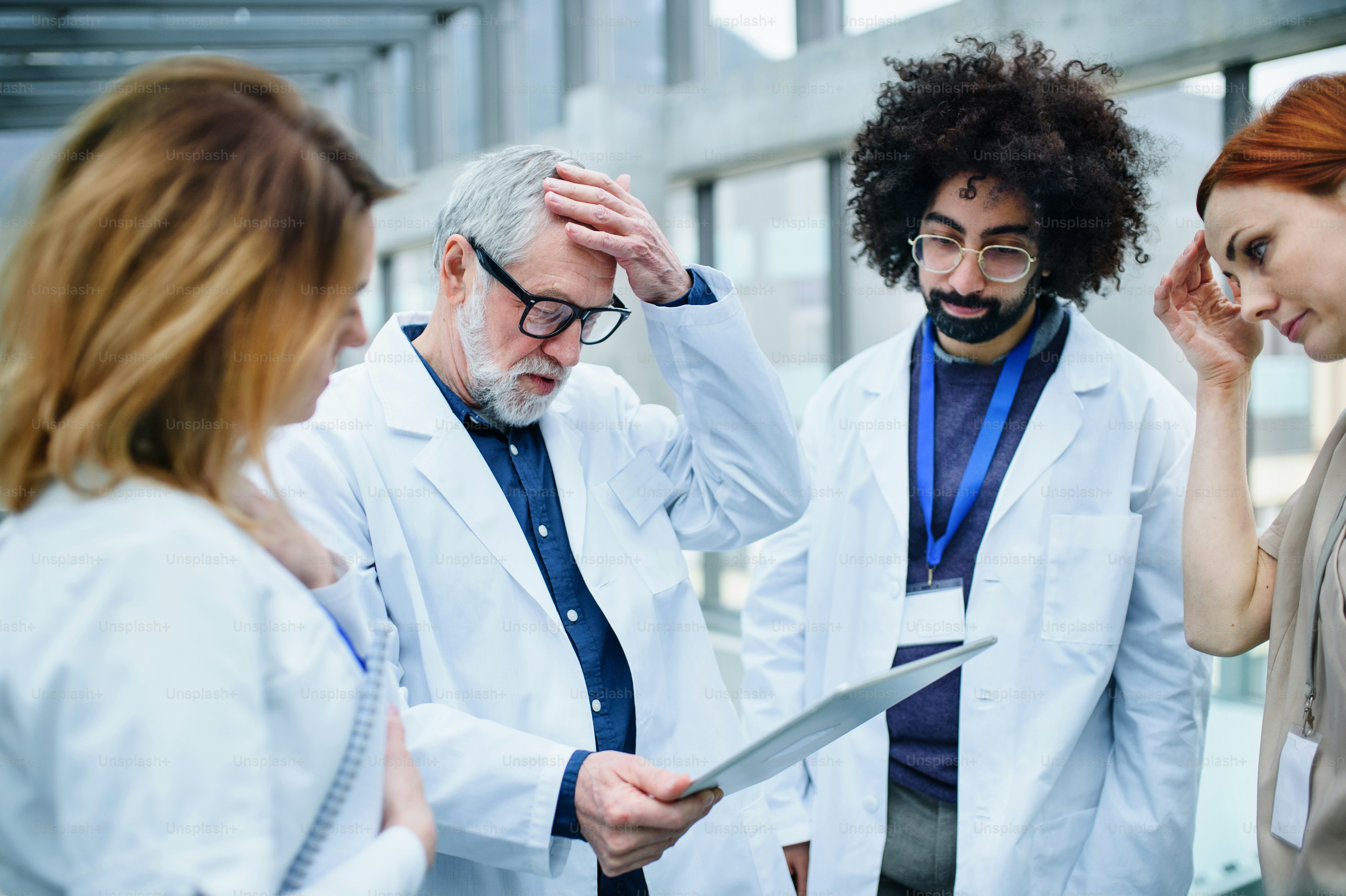 A group of worried doctors with tablet on conference, medical team ...