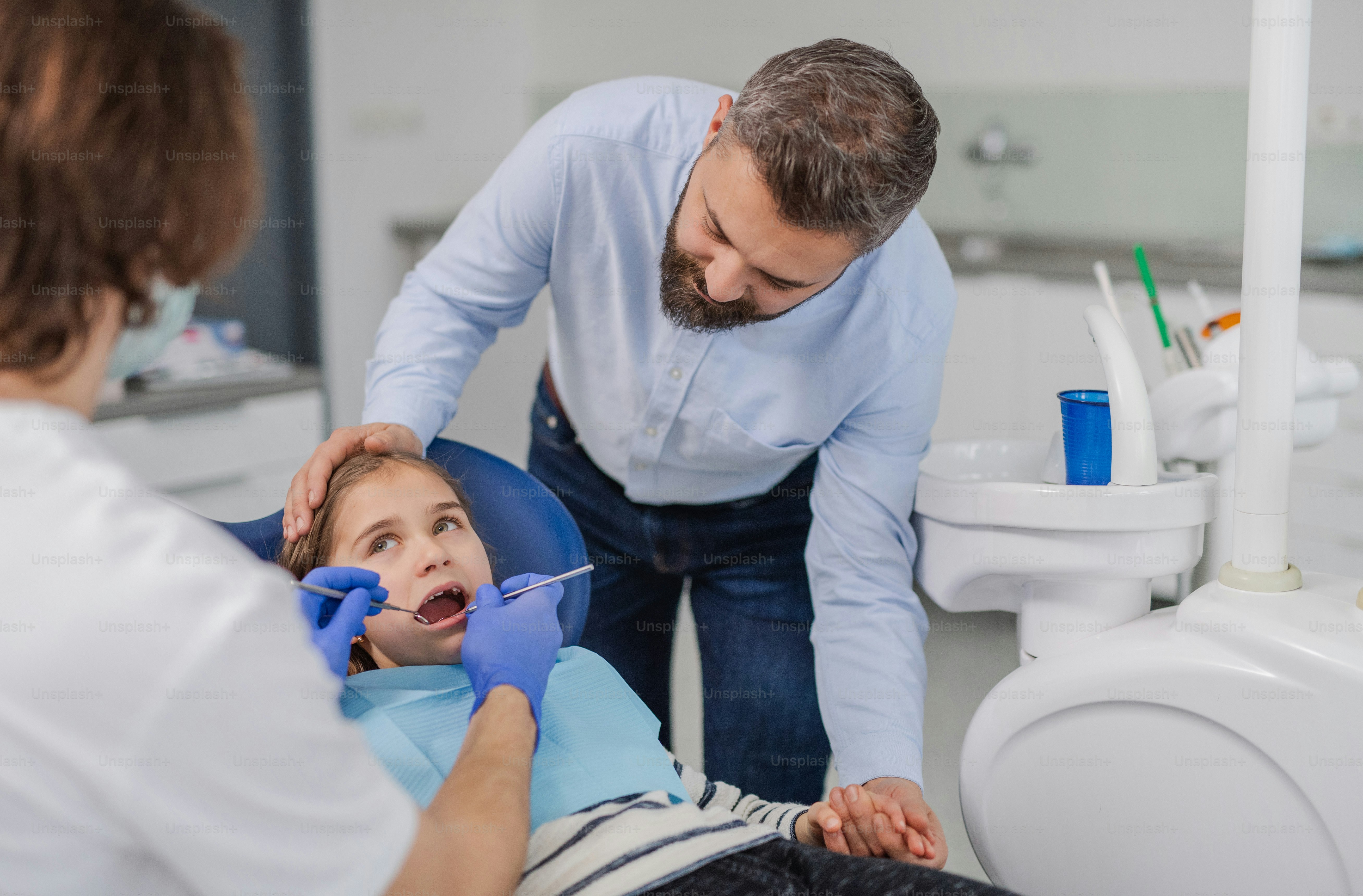 Annual dental check-up of a small child with father in dentist surgery ...