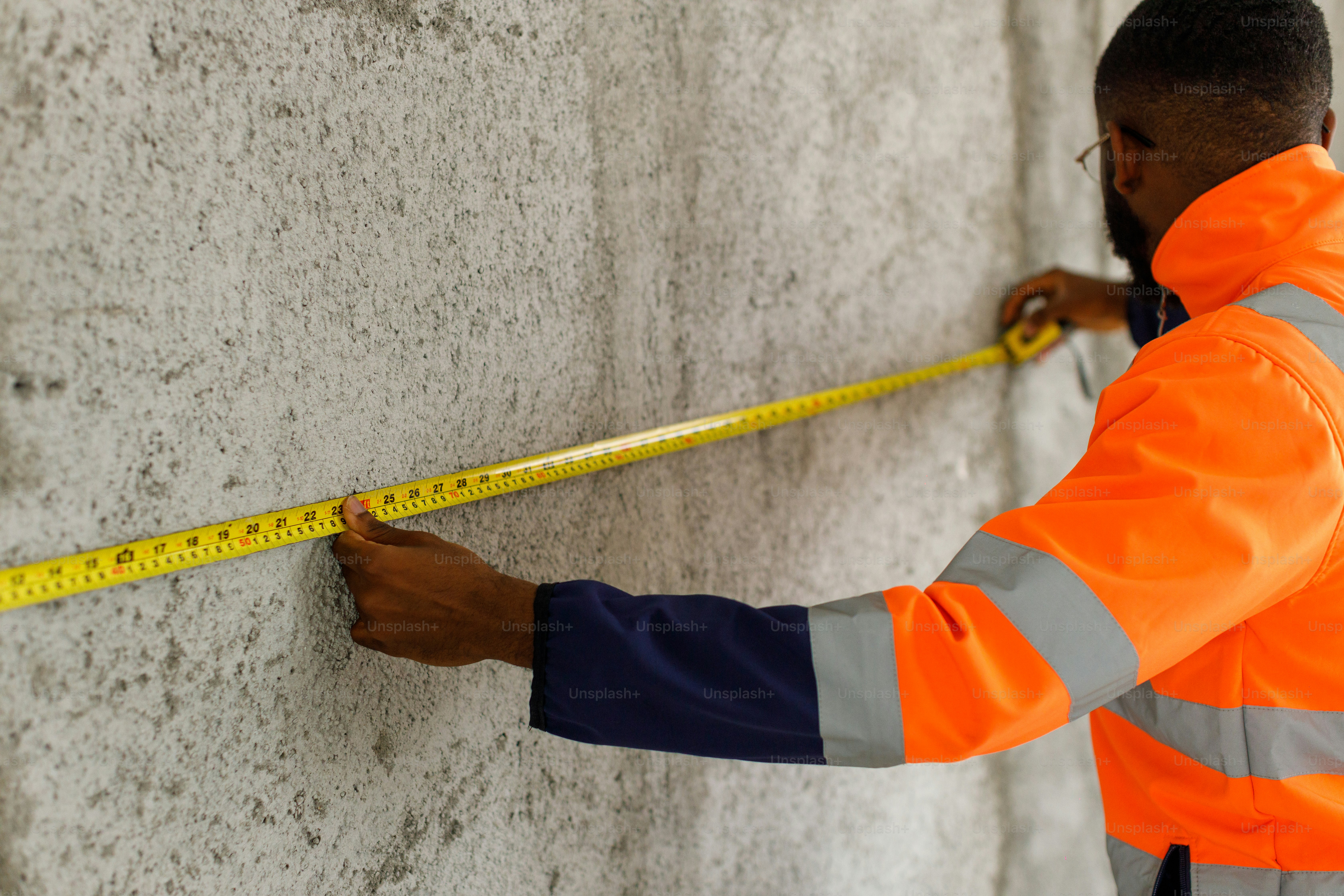 A man measuring a wall with a tape photo – Construction Image on Unsplash