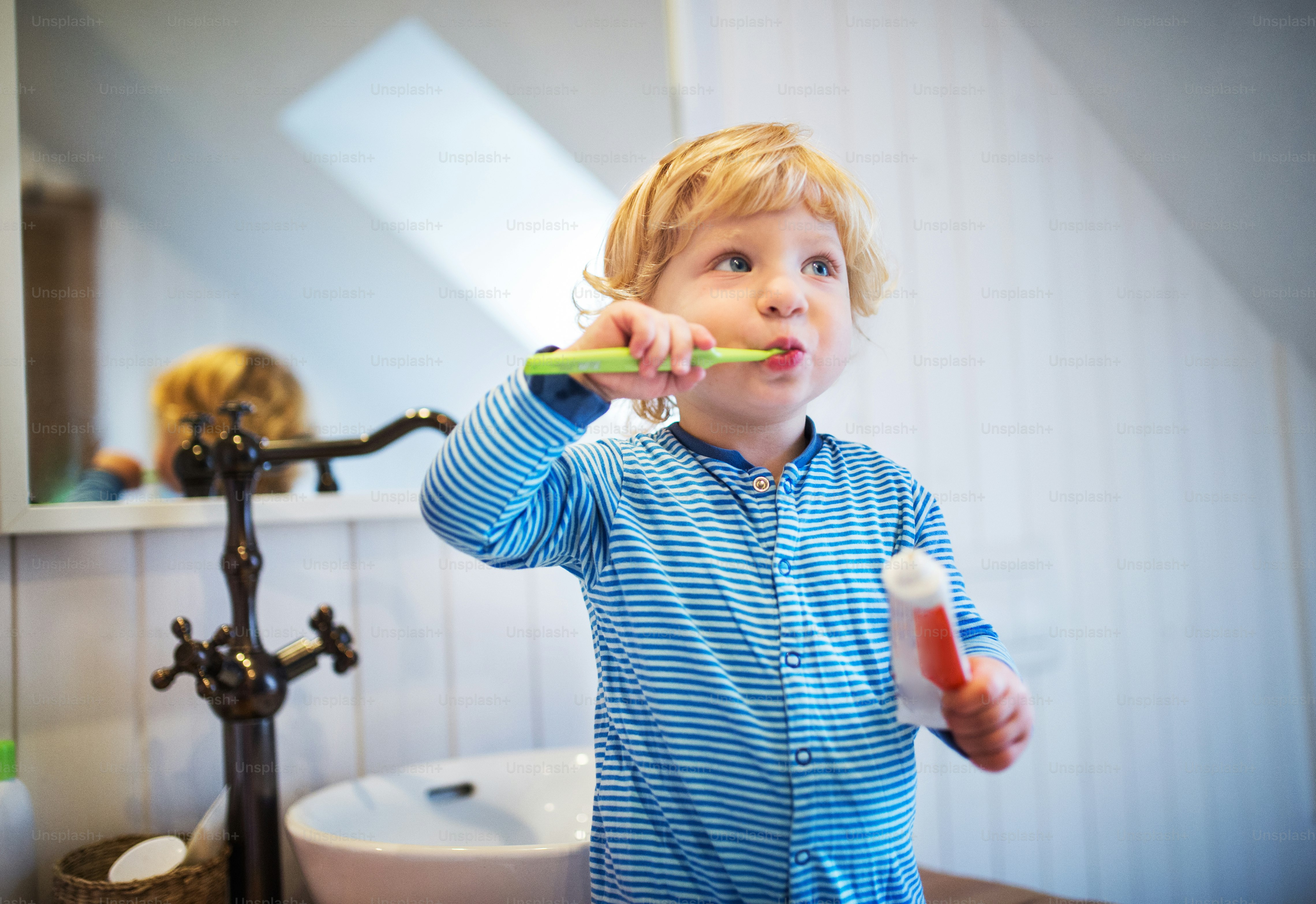 Cute toddler brushing his teeth in the bathroom. Little boy standing on ...