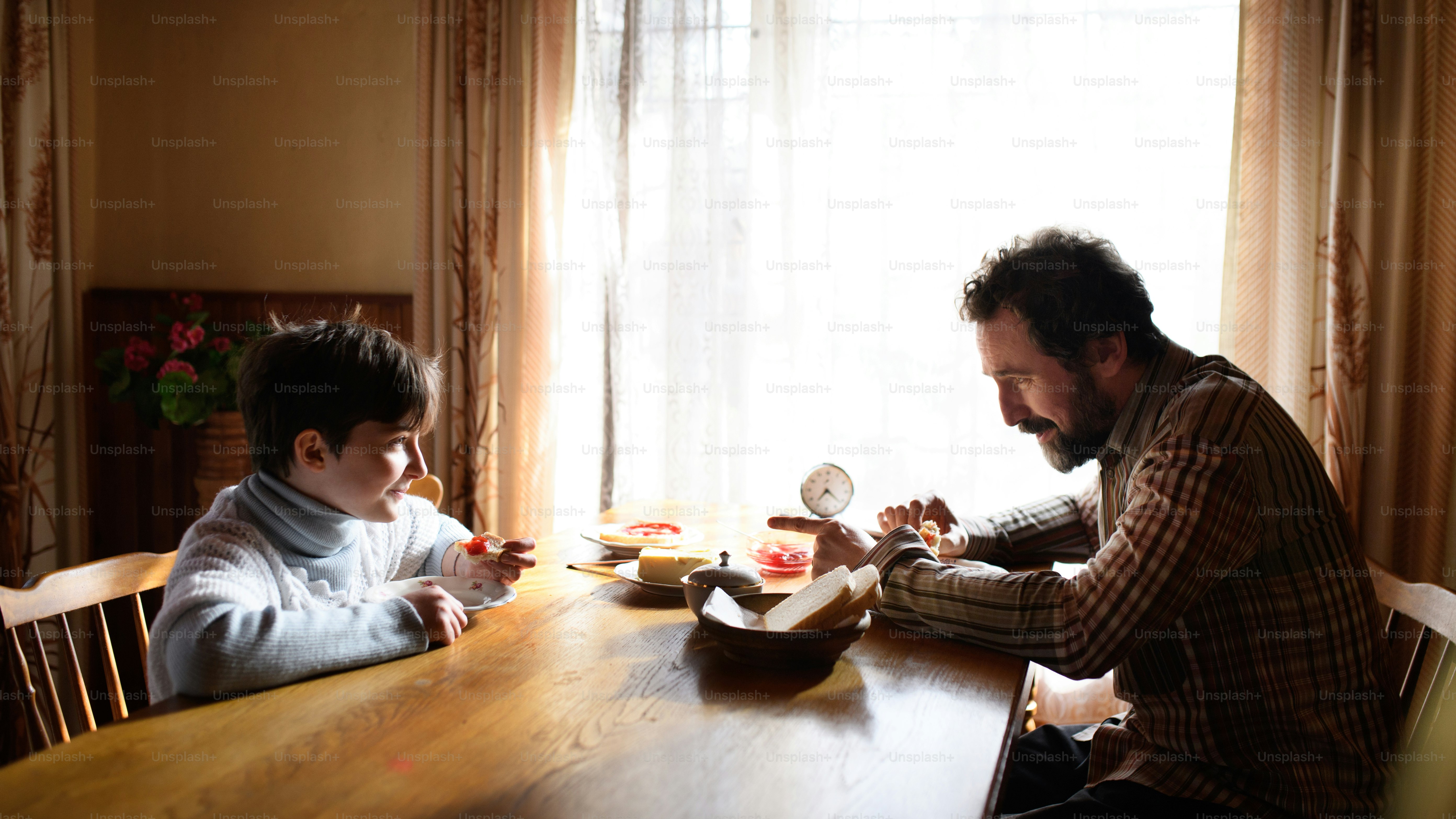 A portrait of poor small girl with father eating indoors at home ...