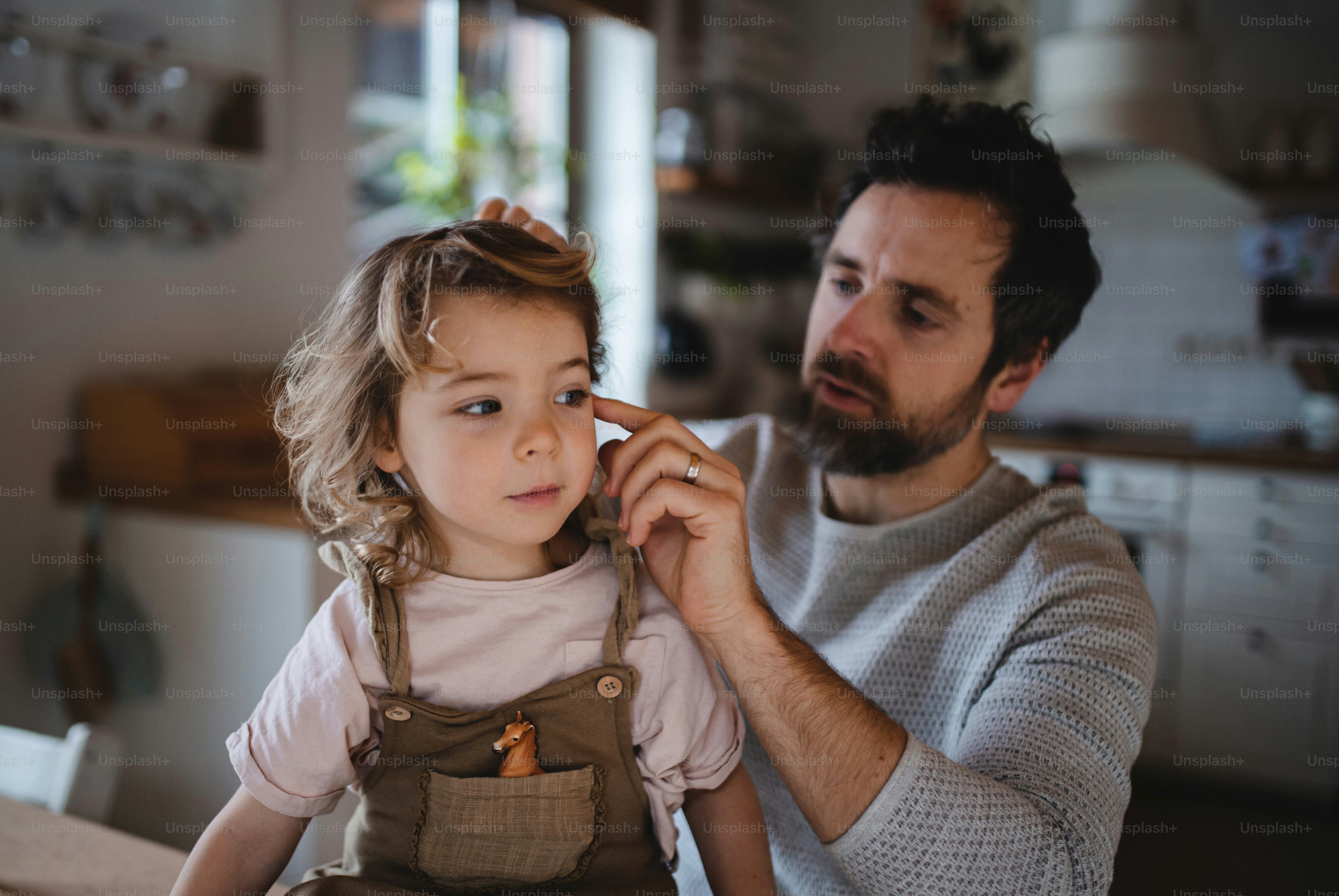 A mature father with small daugther resting indoors at home and combing ...