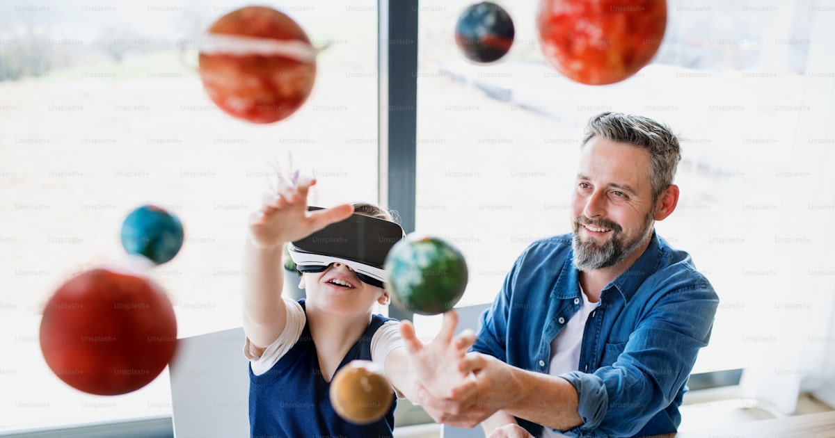 小さな息子とvrゴーグルを持つ成熟した父親が屋内のテーブルに座り、学校のプロジェクトに取り組んでいます。の写真 Unsplashの人の画像