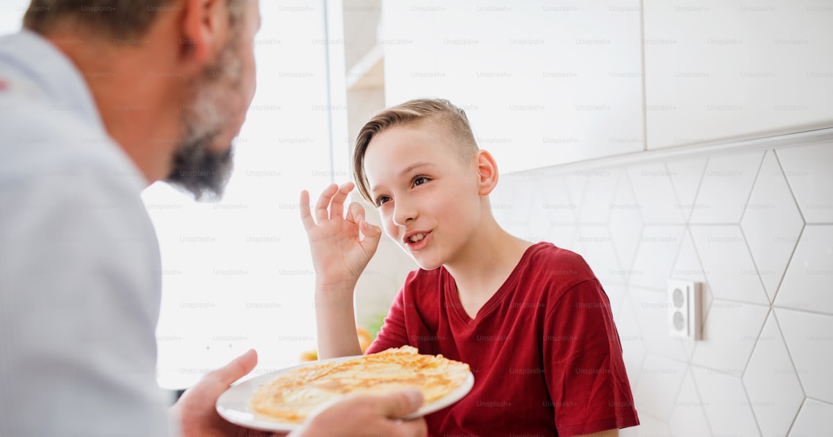 キッチンの屋内で小さな息子を持つ成熟した父親で、パンケーキを作る。の写真 Unsplashの料理の画像