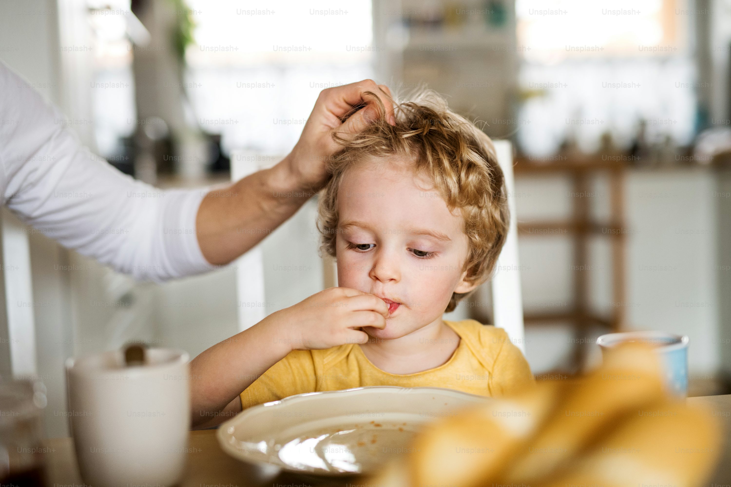A front view of a happy toddler boy sitting at the table at home ... A front view of a happy toddler boy sitting at the table at home ...