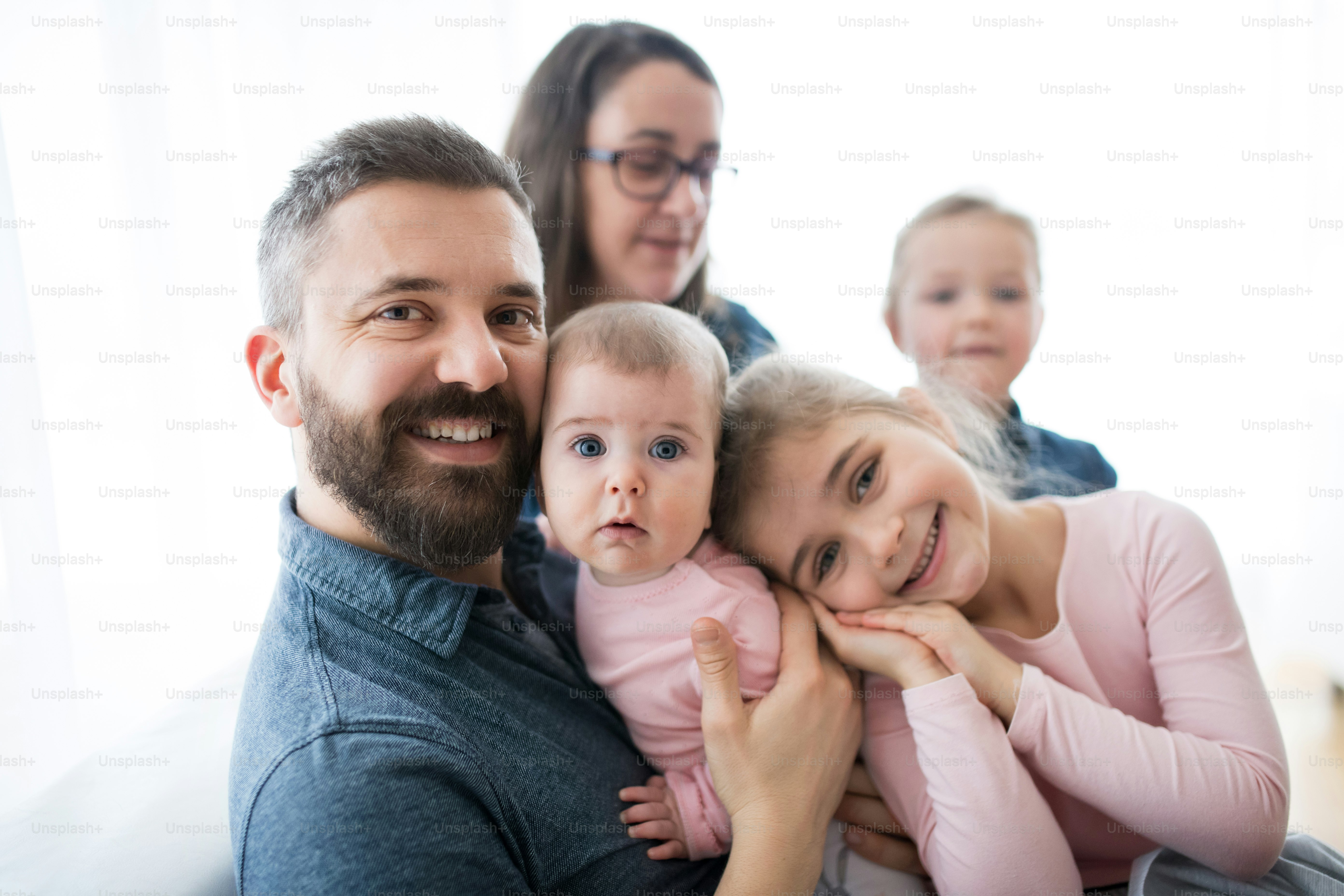 A portrait of happy young family with small children sitting indoors on ...