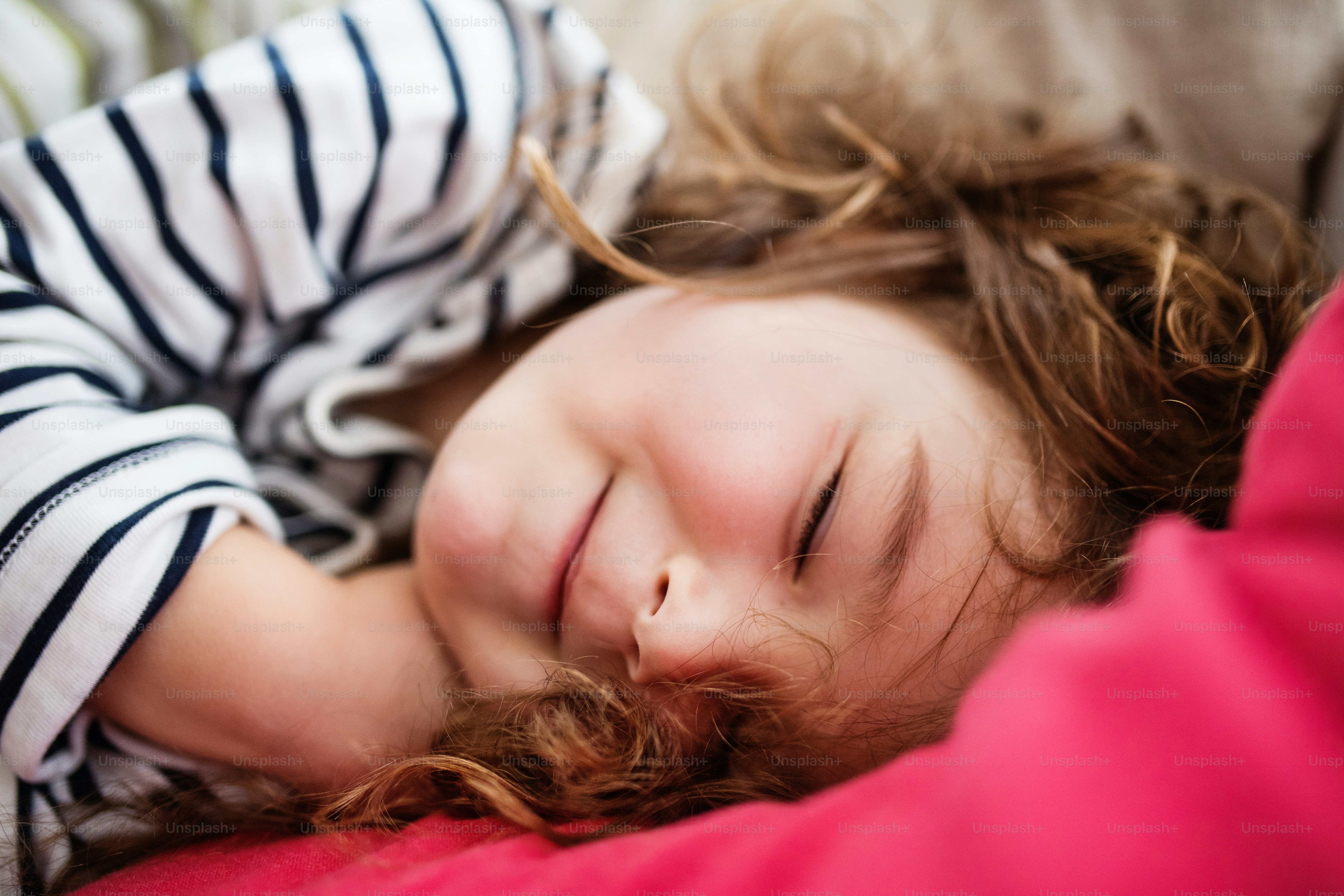 A cute small happy girl in striped t-shirt at home sleeping. close up ...