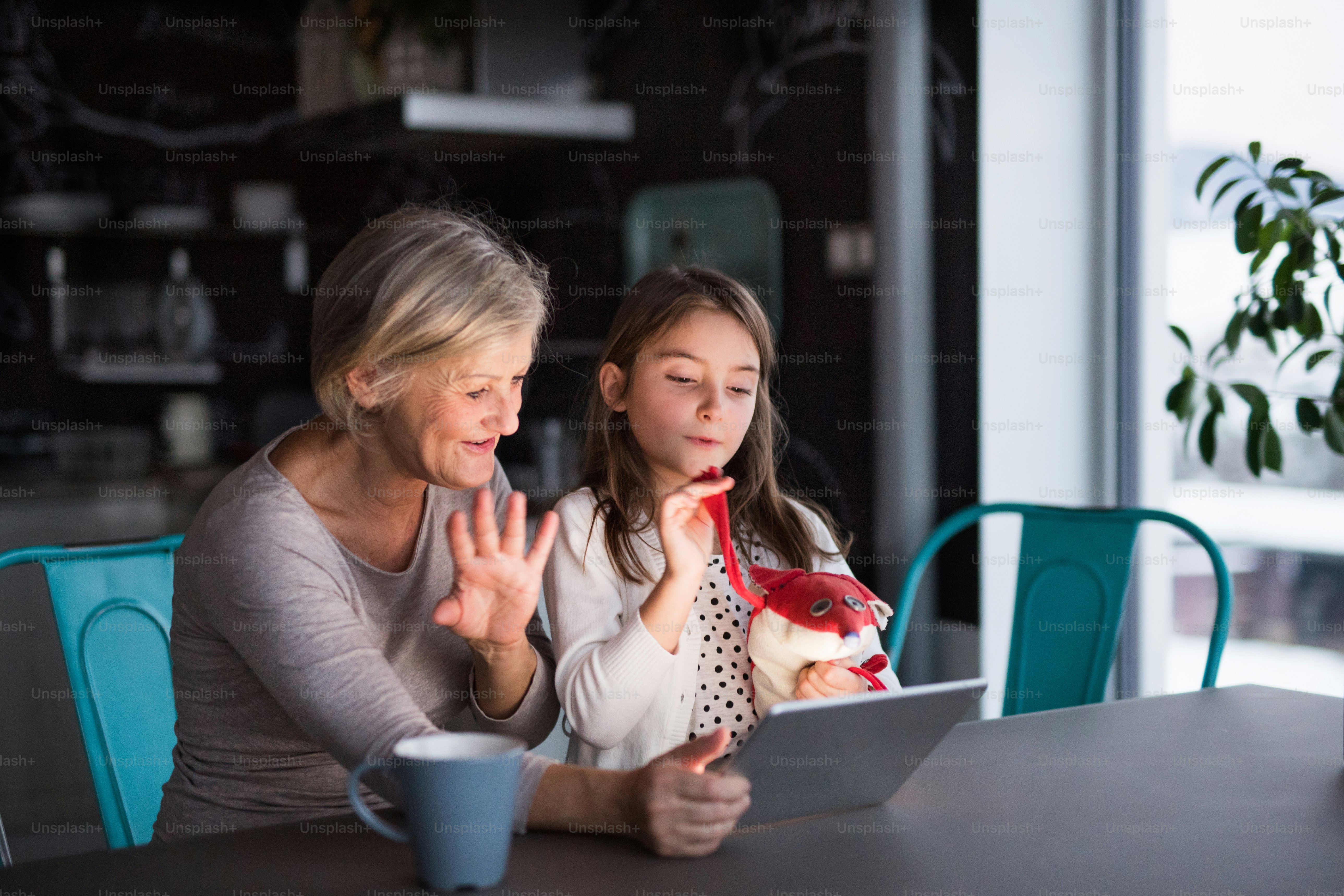 A small girl and her grandmother with tablet at home. Family and ...