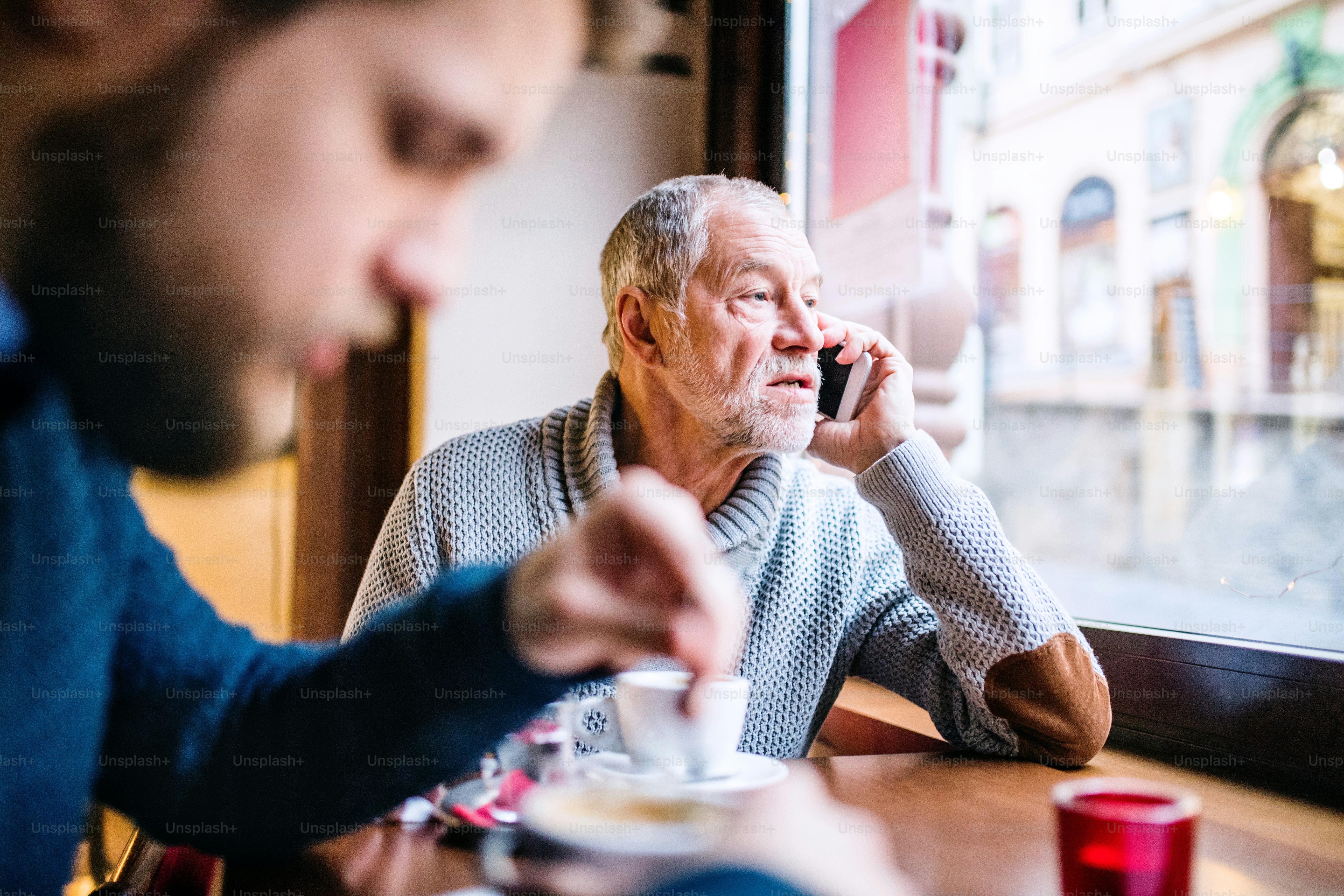 Senior father with smartphone and his young son in a cafe. Old man ...