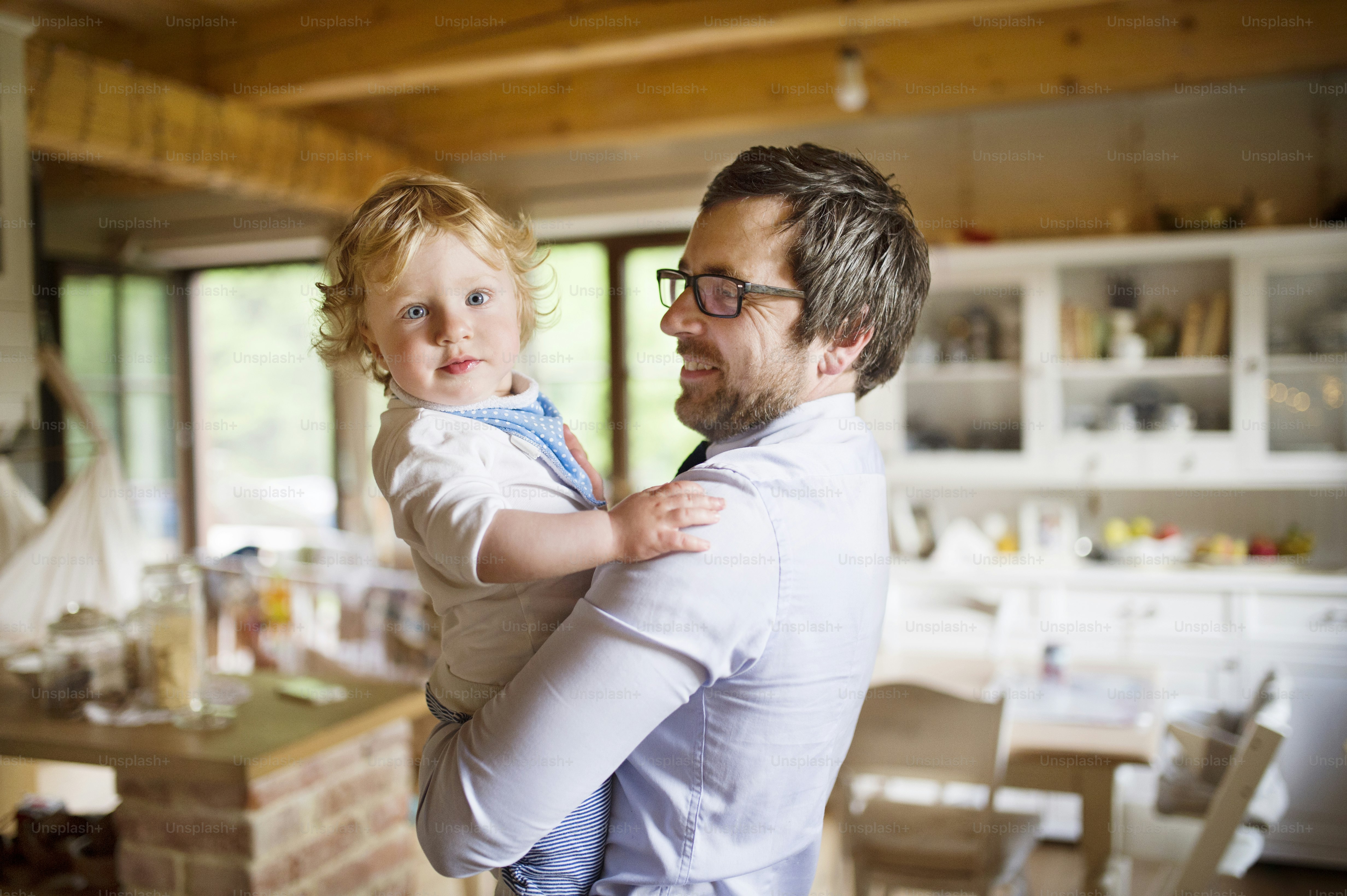 Young businessman coming home from work, in the kitchen with his little ...