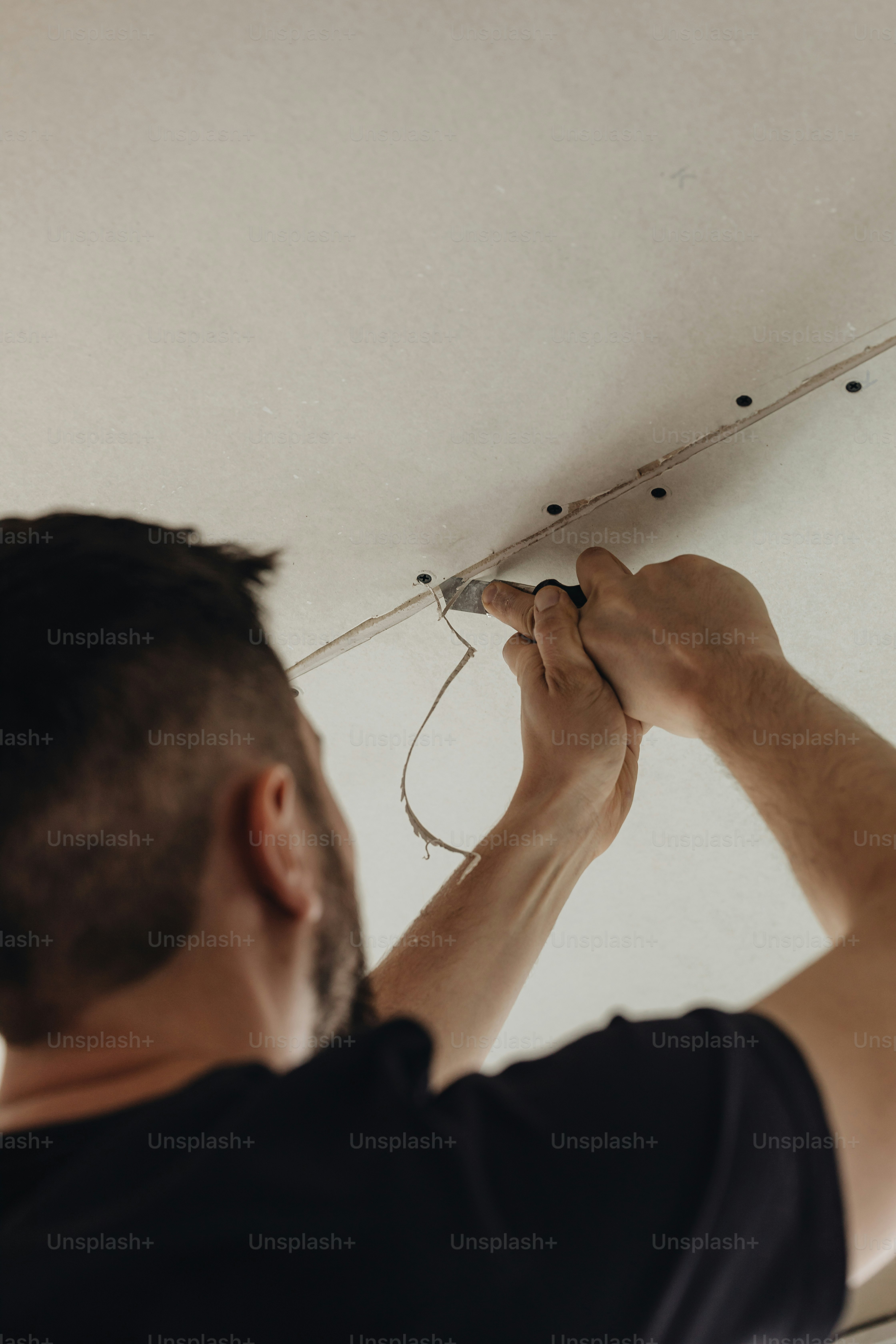 A man is fixing a light fixture in a room photo – Renovation Image on ...