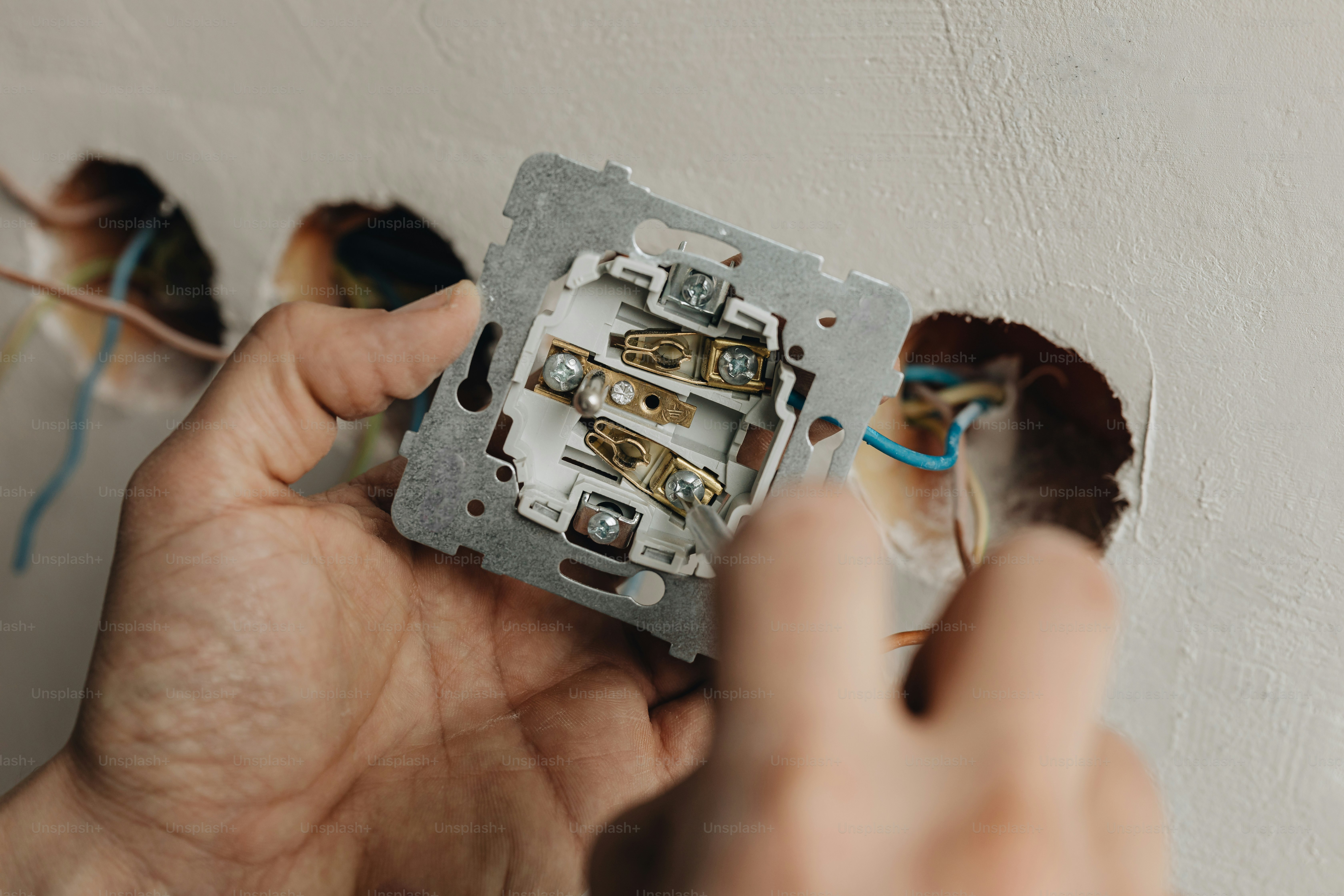 A person is fixing a light switch on a wall photo – Electrician Image ...