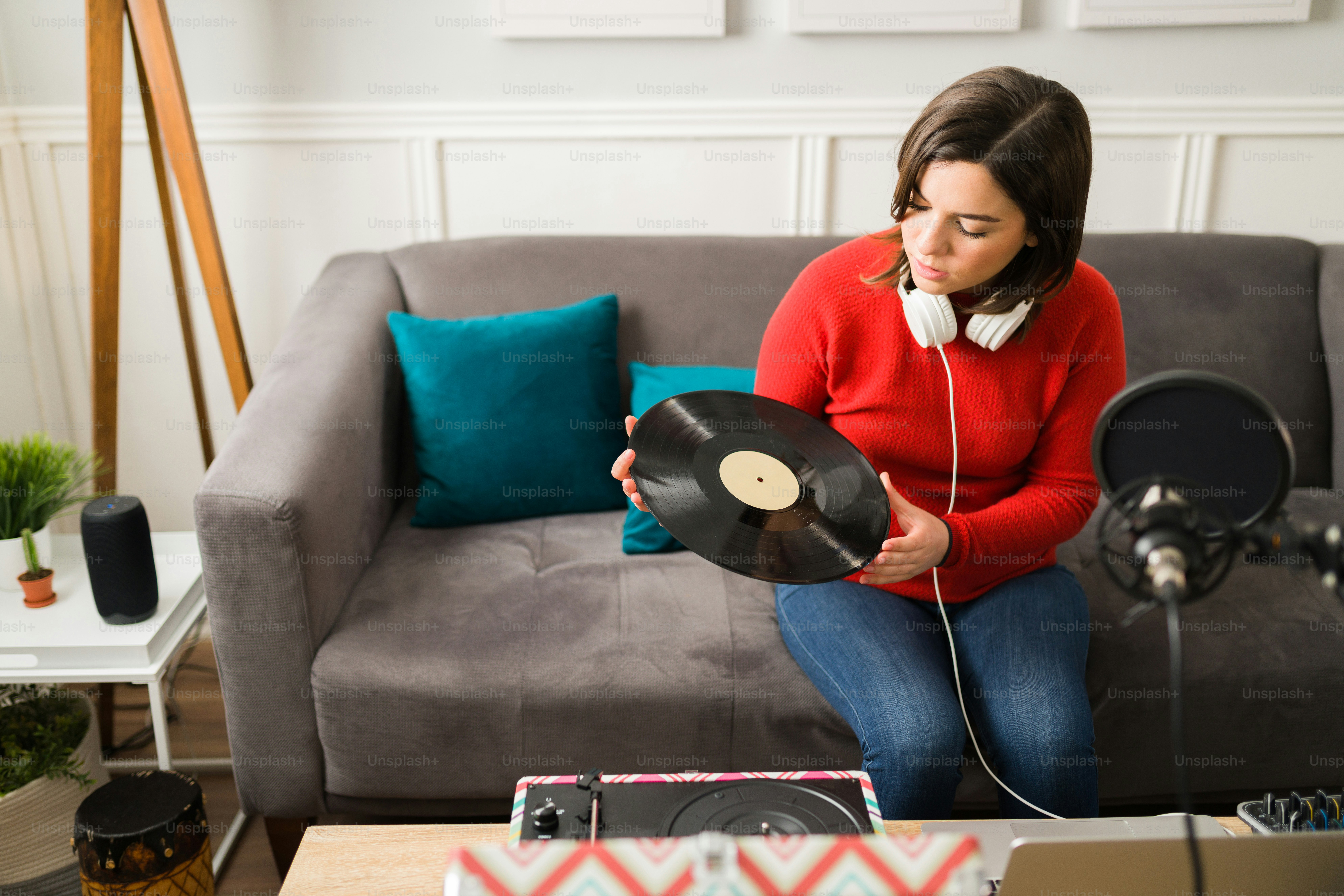 Attractive young woman putting a vinyl record on the turntable to get ...