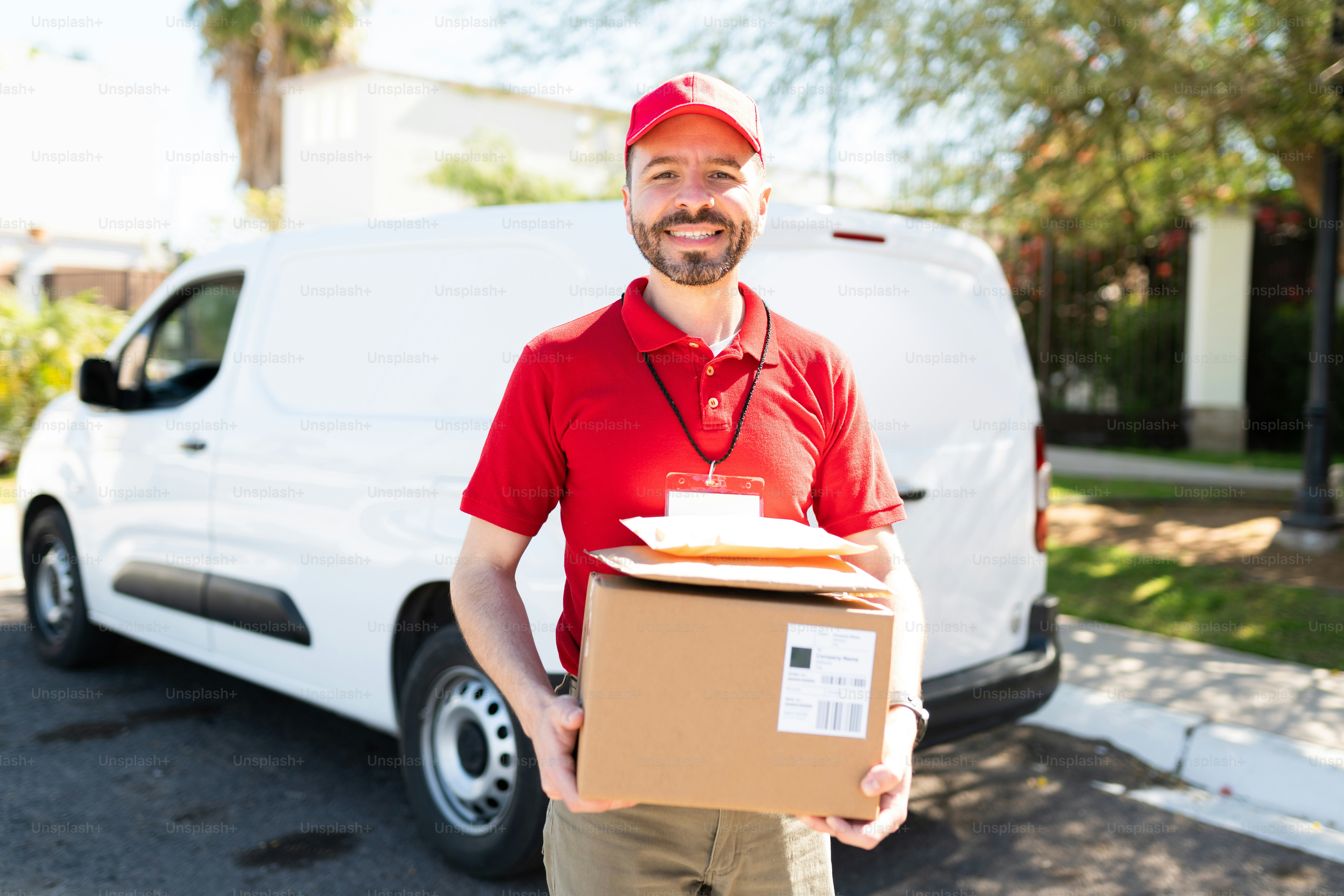 Portrait of a happy delivery courier with a white van smiling while ...
