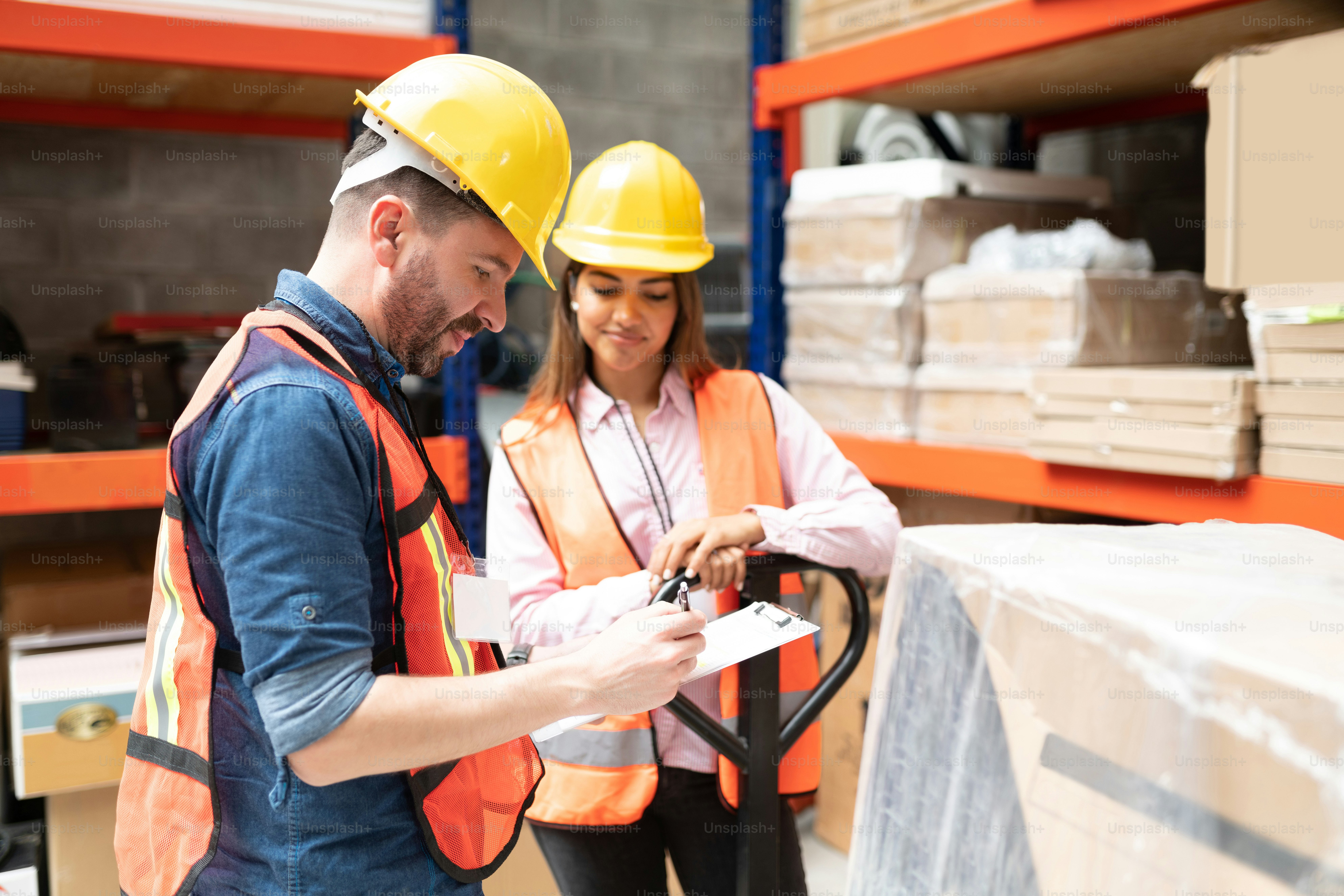 Confident supervisor examining list while standing by coworker at ...
