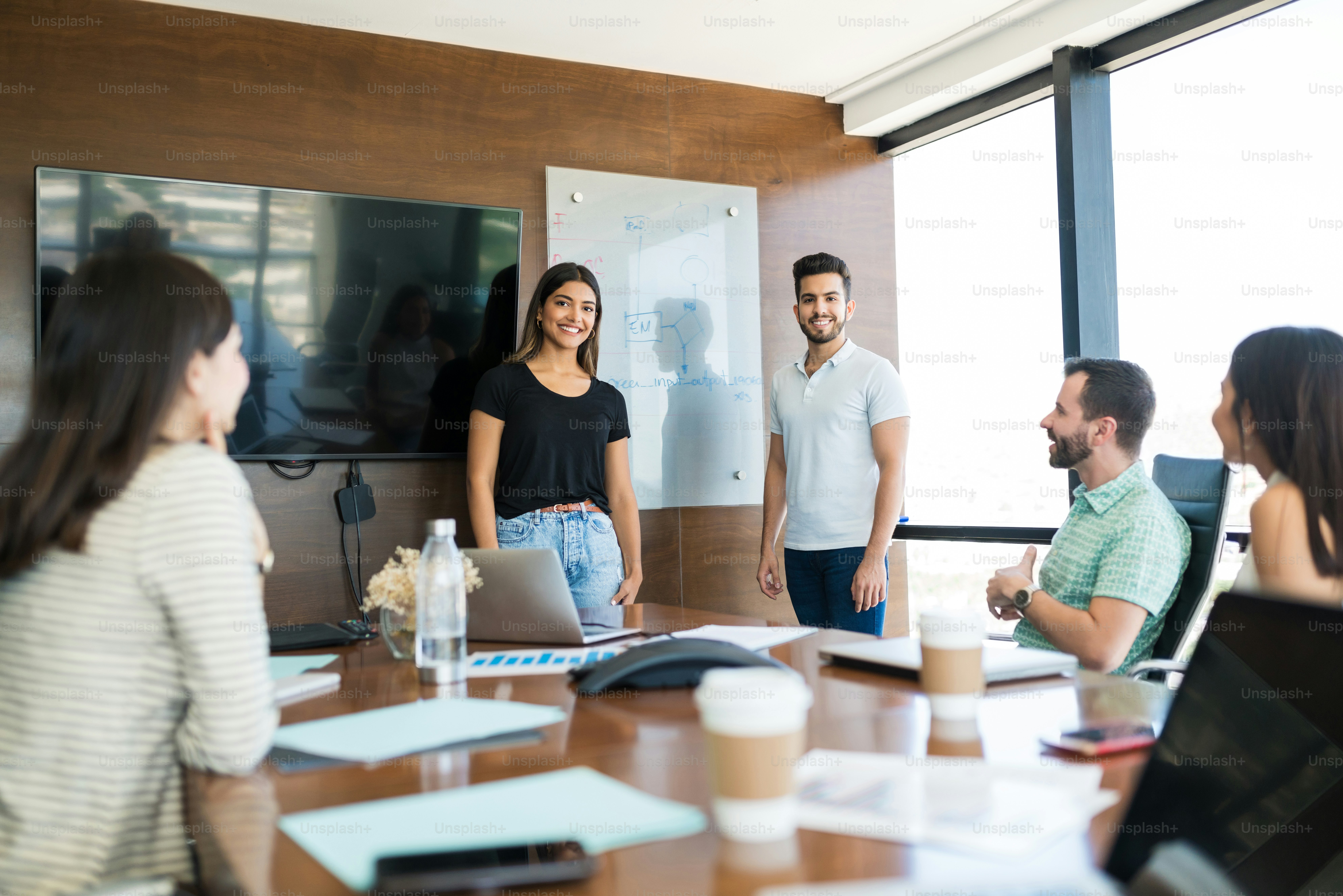 Portrait of businesswoman and businessman giving presentation to team ...