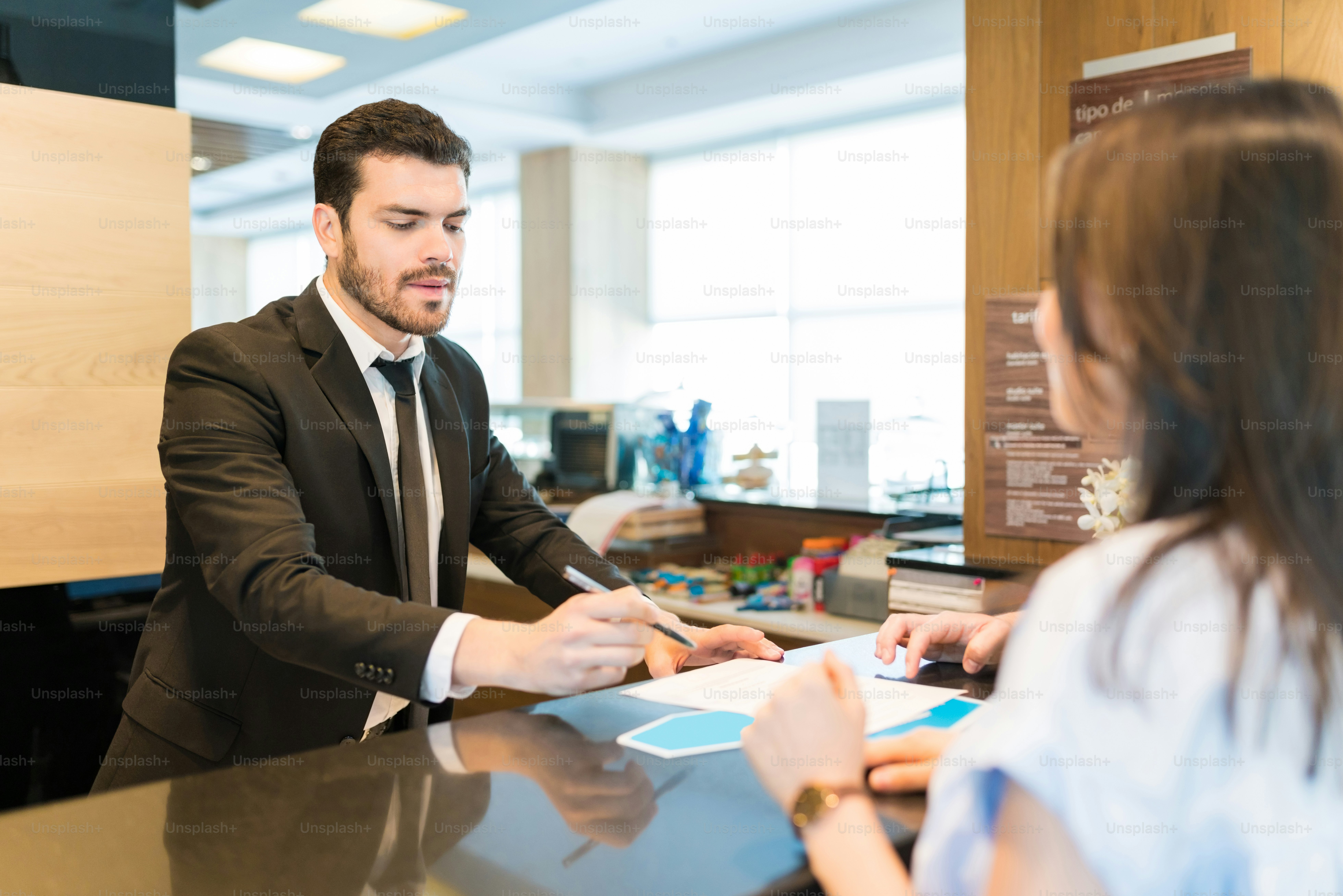Mid adult couple making reservation while standing with clerk at ...