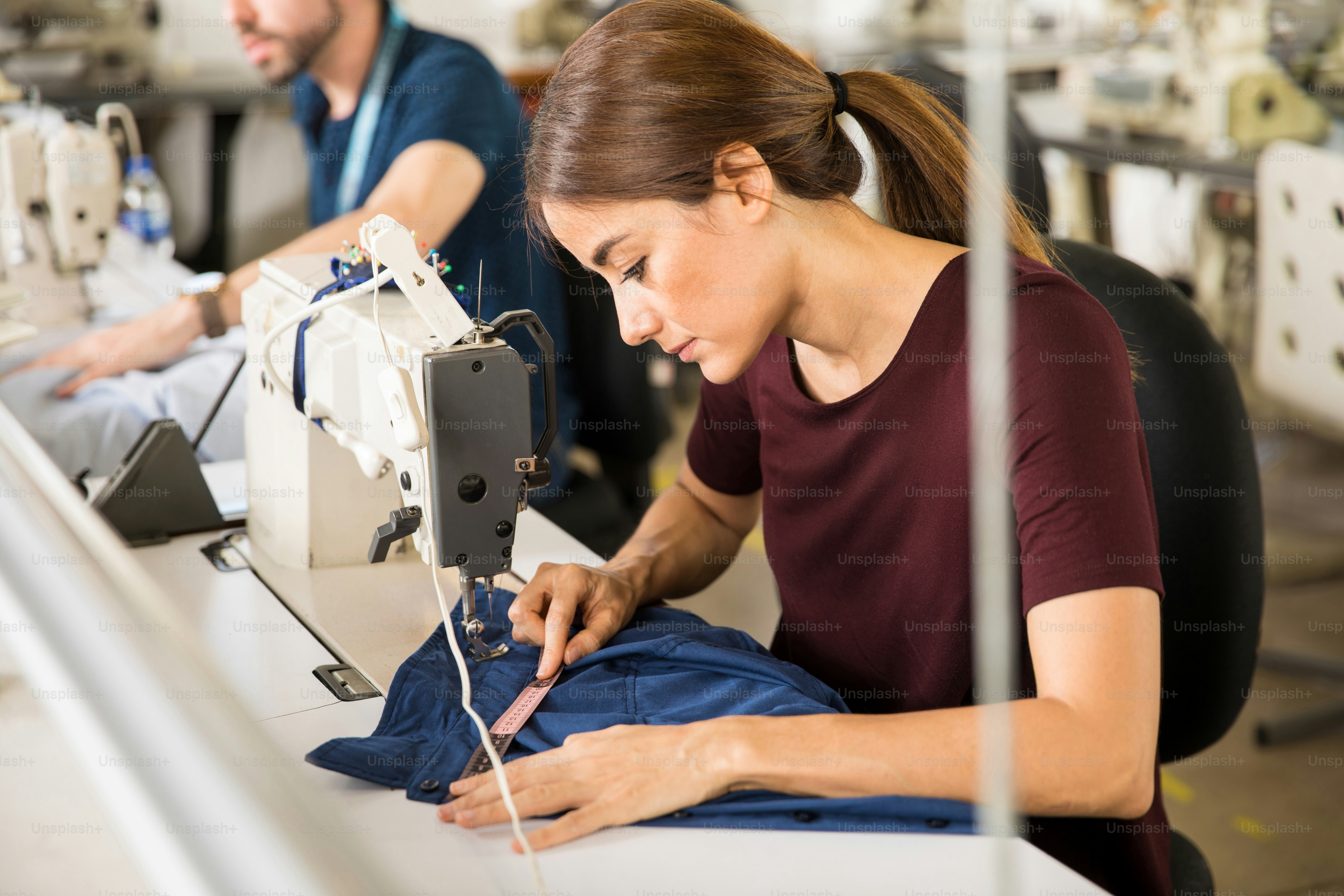 Young brunette working as a seamstress and measuring a shirt after ...