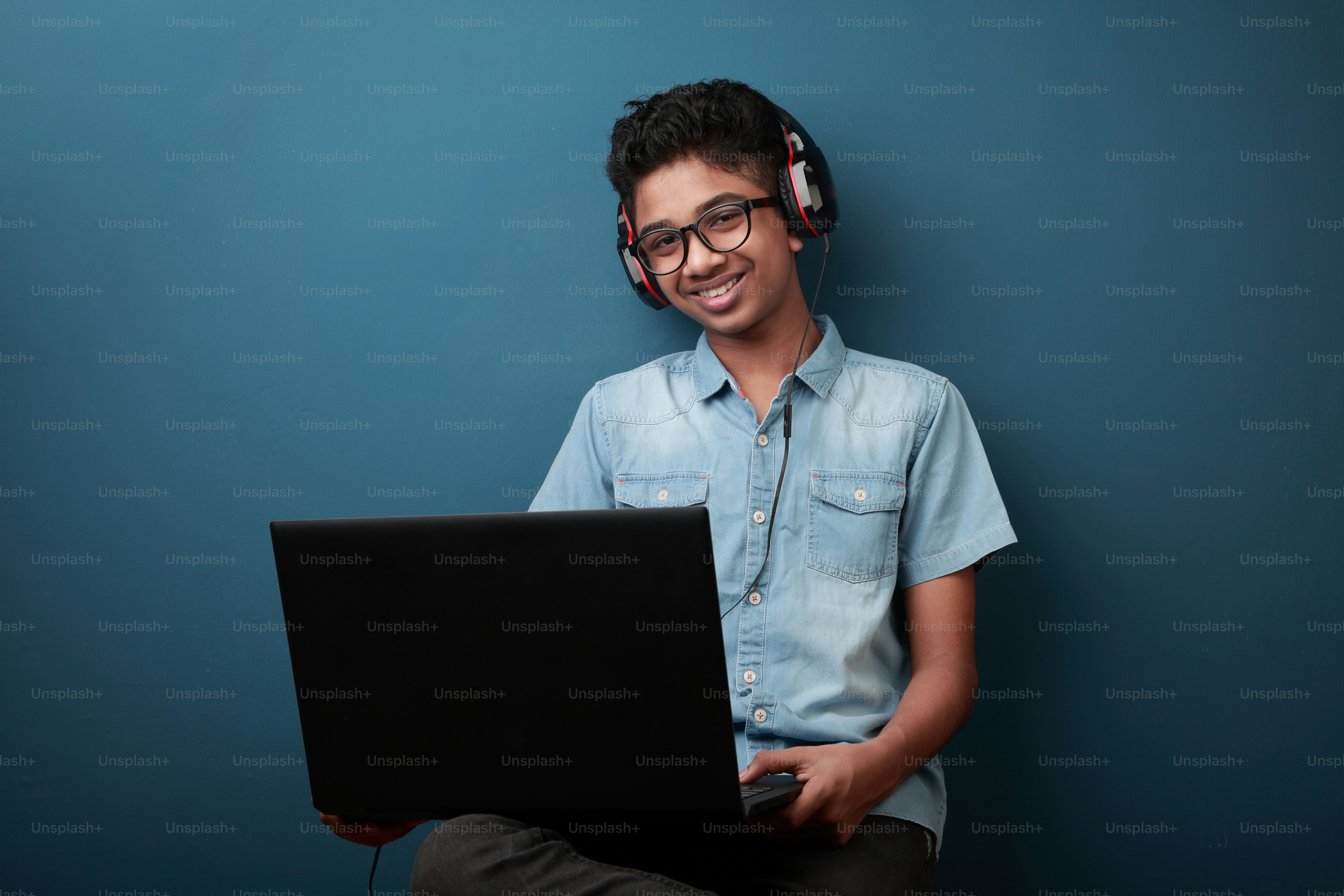 Happy young boy wearing headset smiles while learning through laptop ...