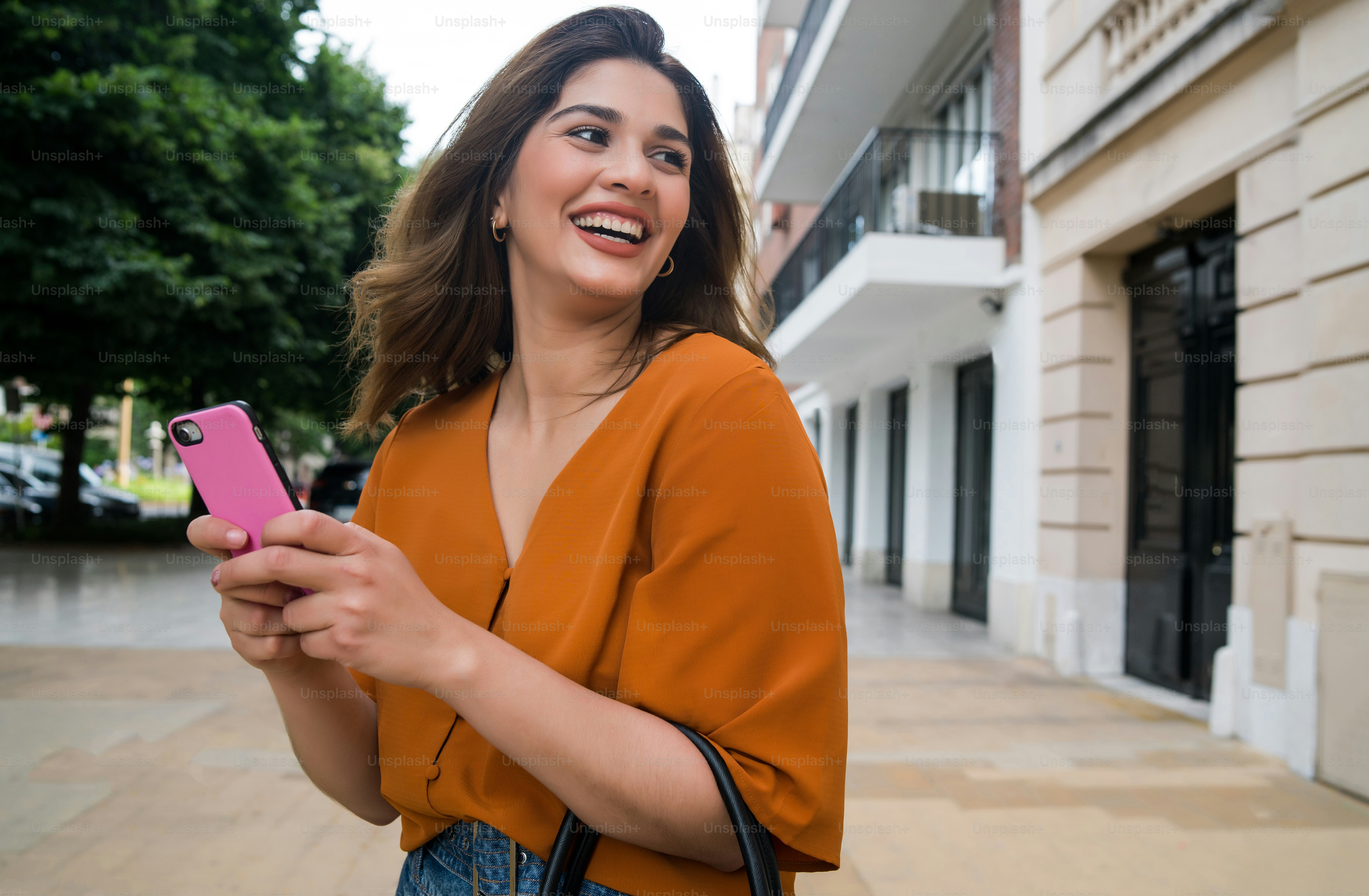 Young woman using her mobile phone while standing outdoors on the ...