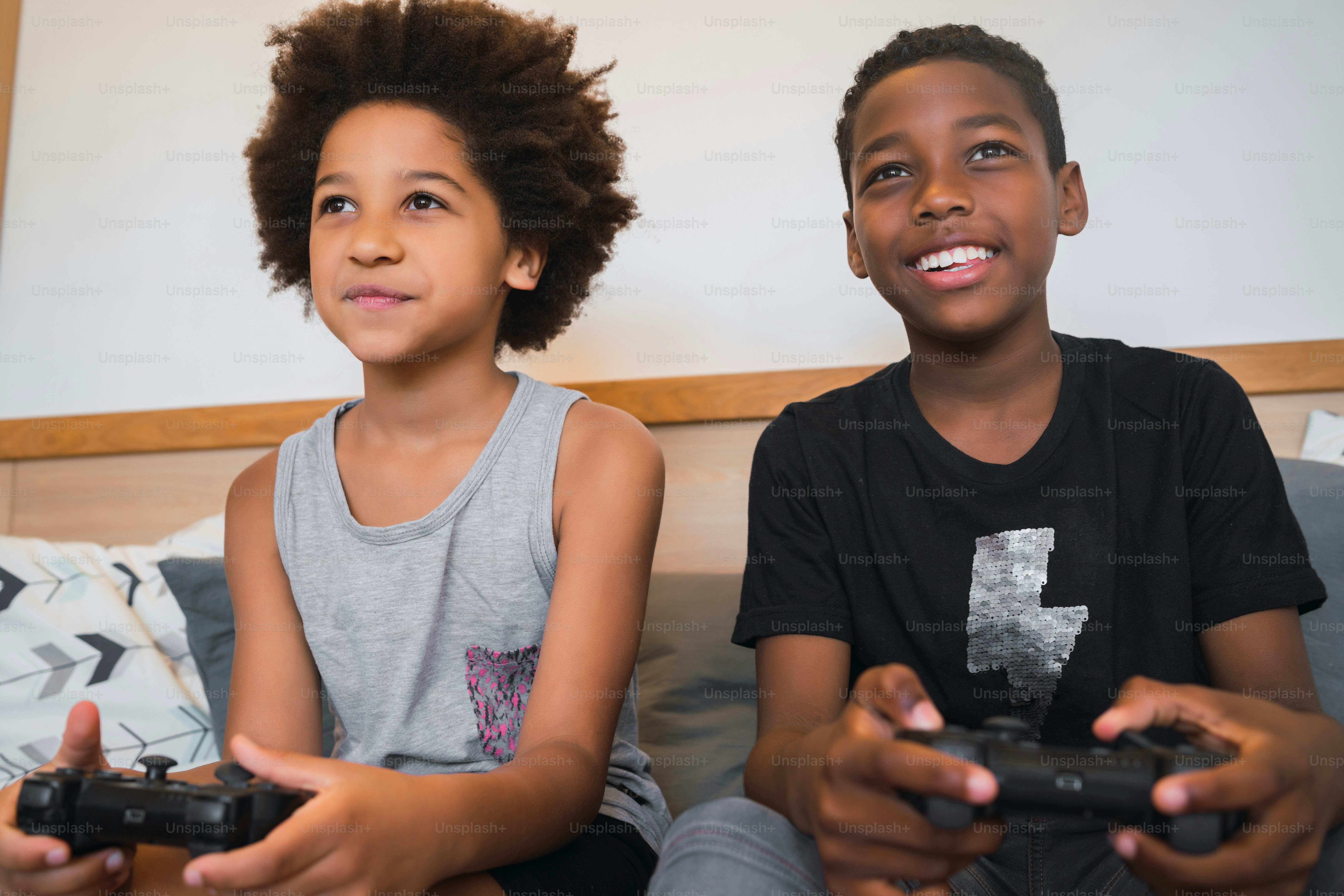 Portrait of two Afro American brothers playing video games at home ...