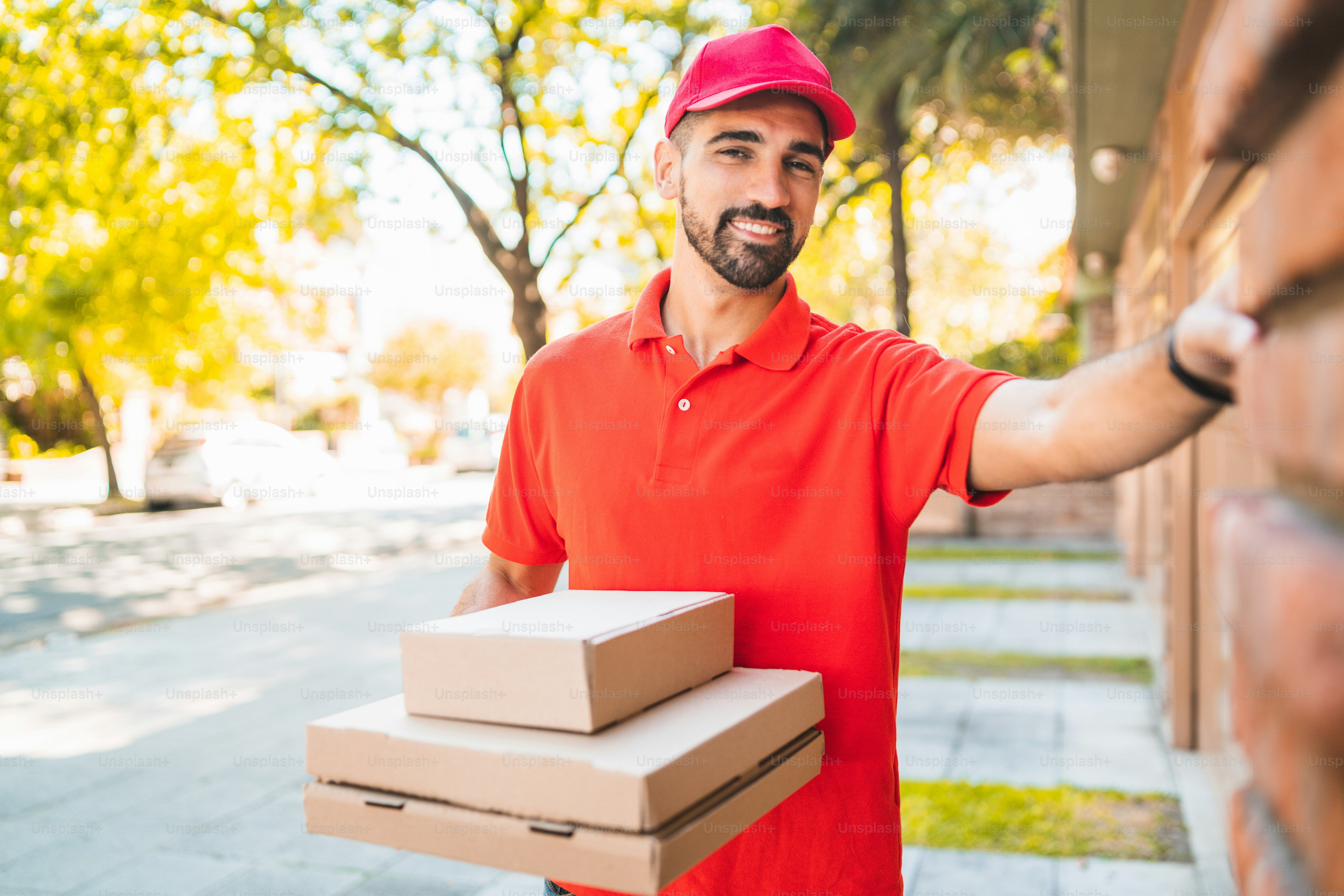 Portrait of a delivery man with cardboard pizza box outdoors in street ...